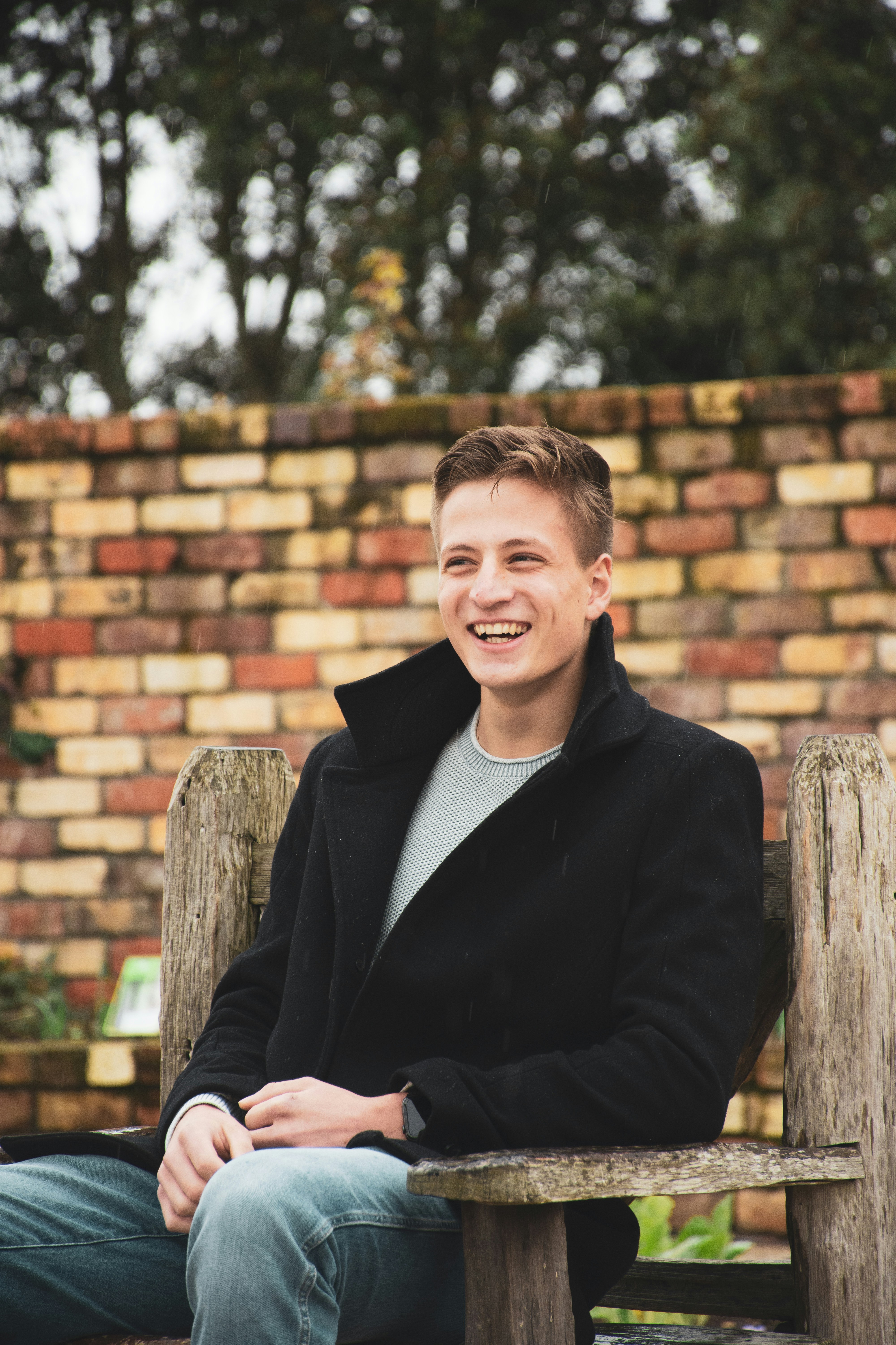 Smiling in the Park: A Casual Portrait Against a Brick Wall