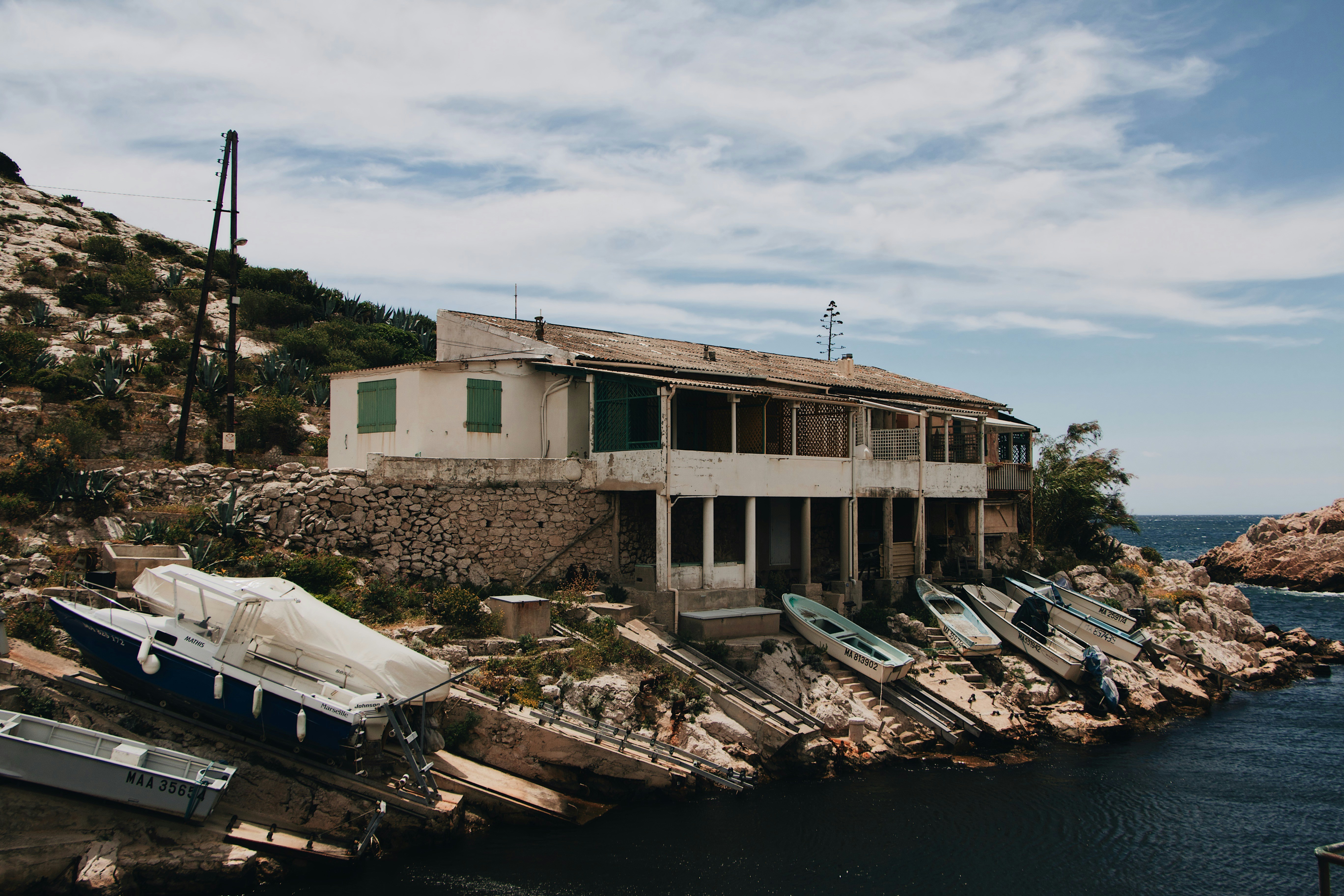Weathered boathouse on a rocky cove as boats rest along the quay
