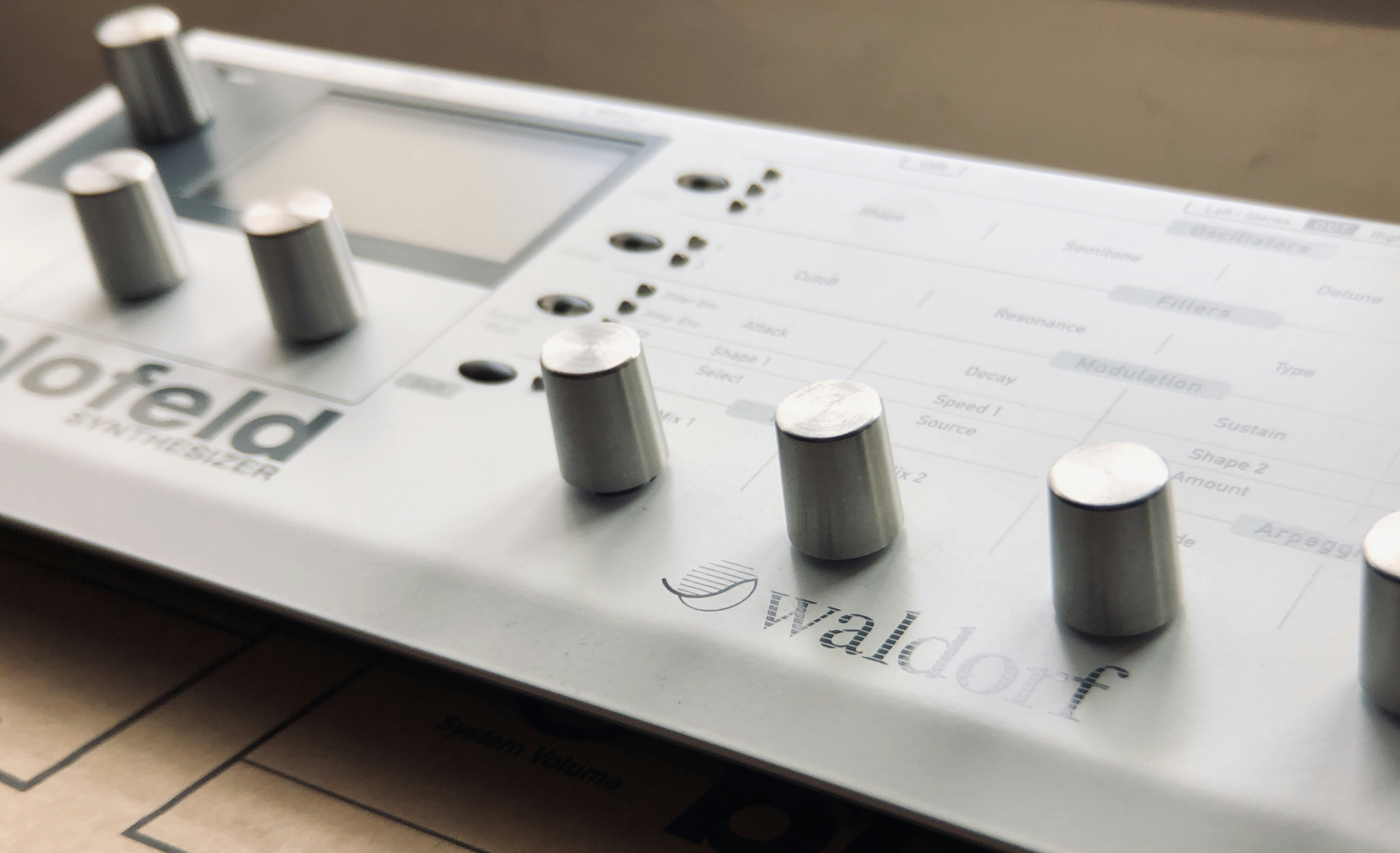 Close-up of a Waldorf audio mixer with metal knobs and labeled controls, emphasizing tactile controls and portable studio hardware.