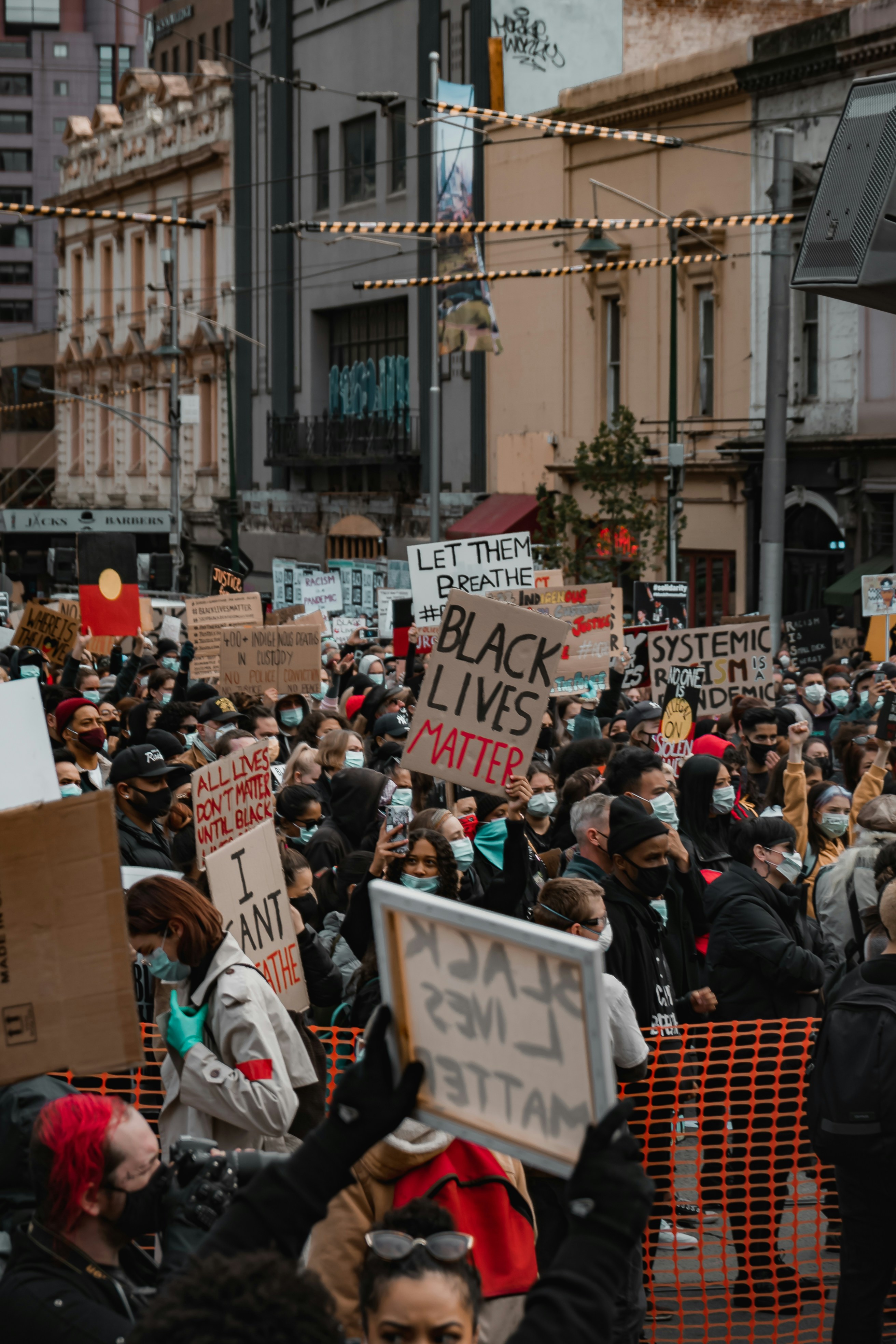 Crowd holding protest signs advocating for racial equality and justice in a city square.