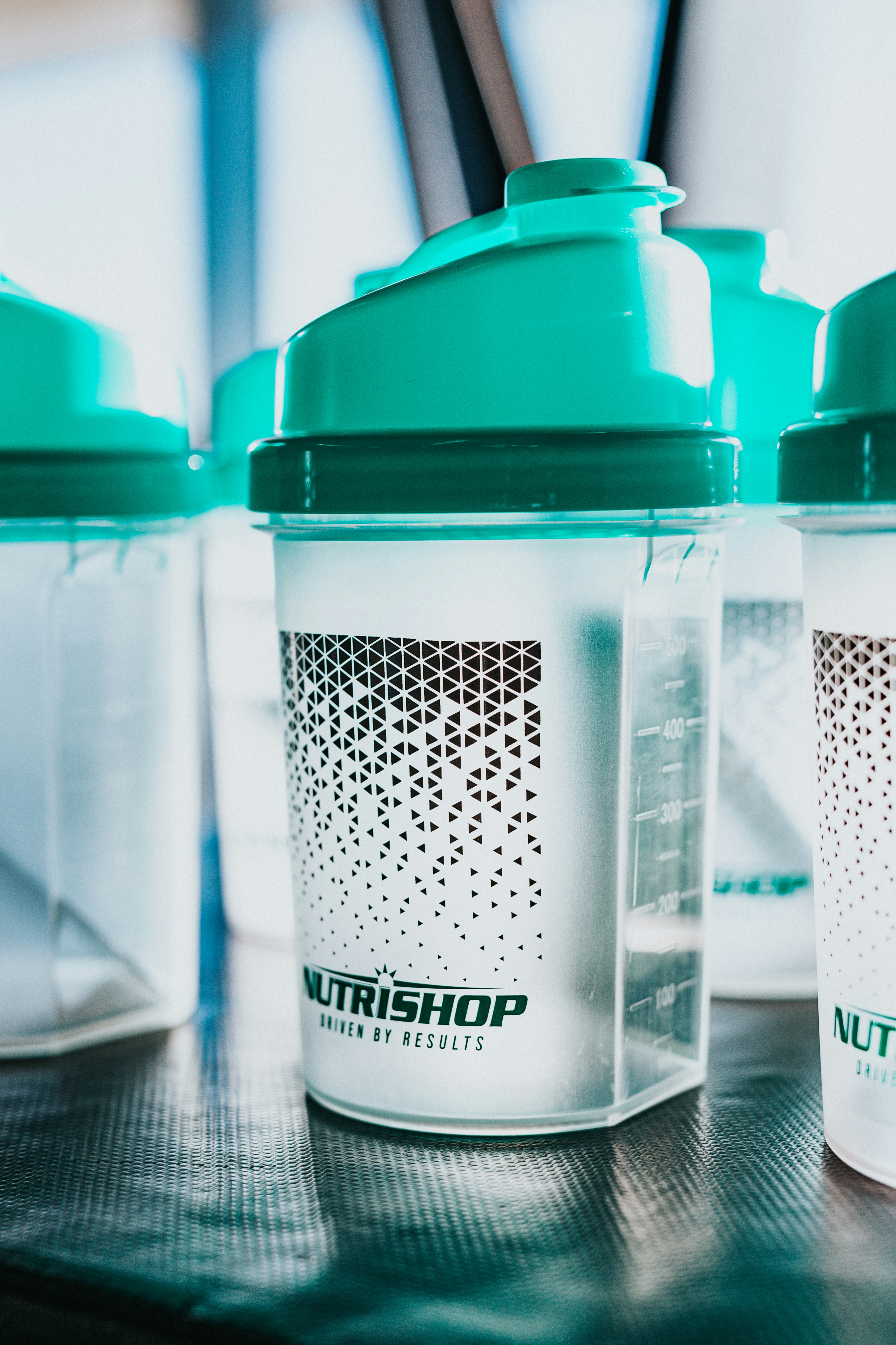 Turquoise-Top Protein Shaker Trio on a Dark Work Surface