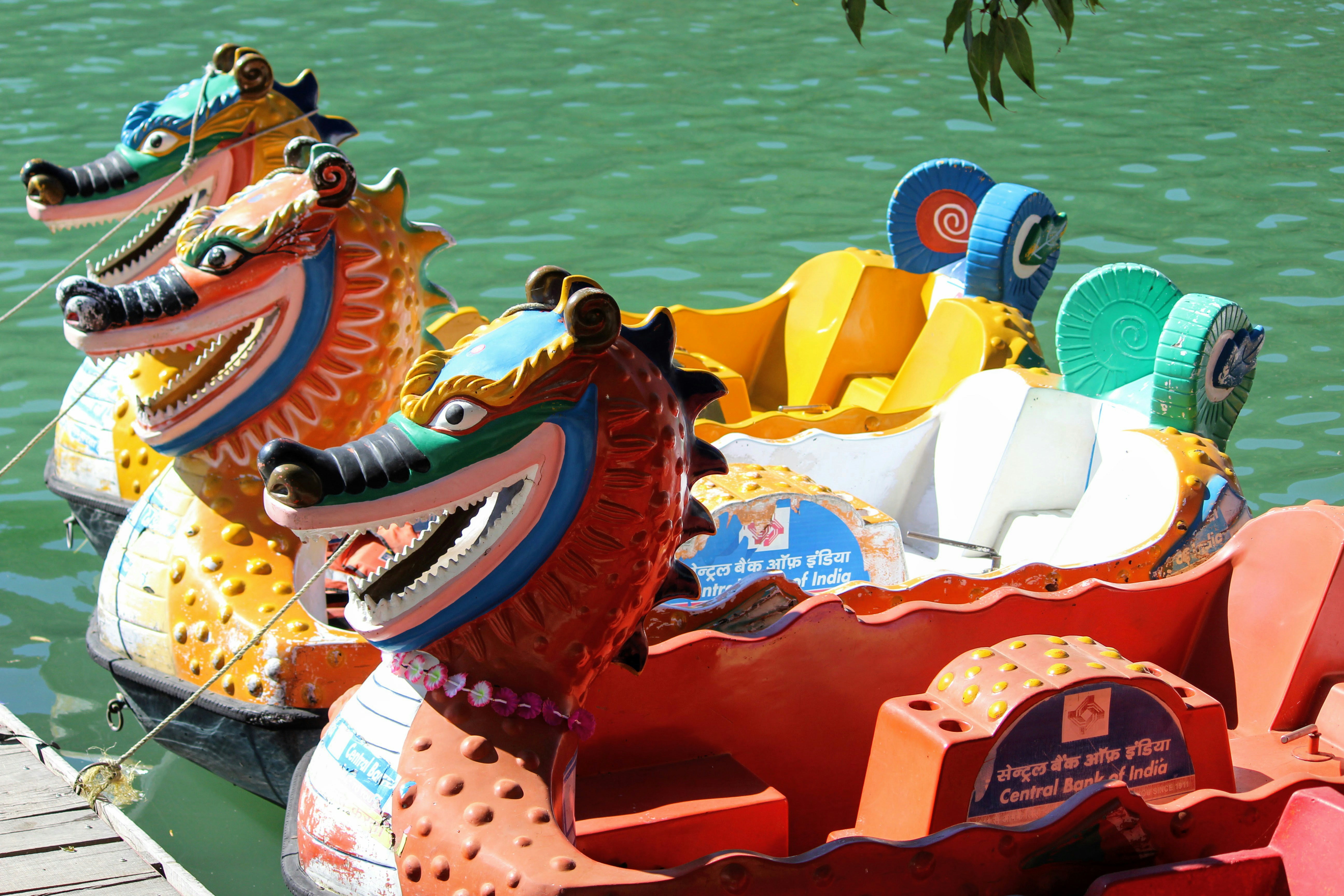 Dragon-Head Pedal Boats Parade Along a Turquoise Riverside