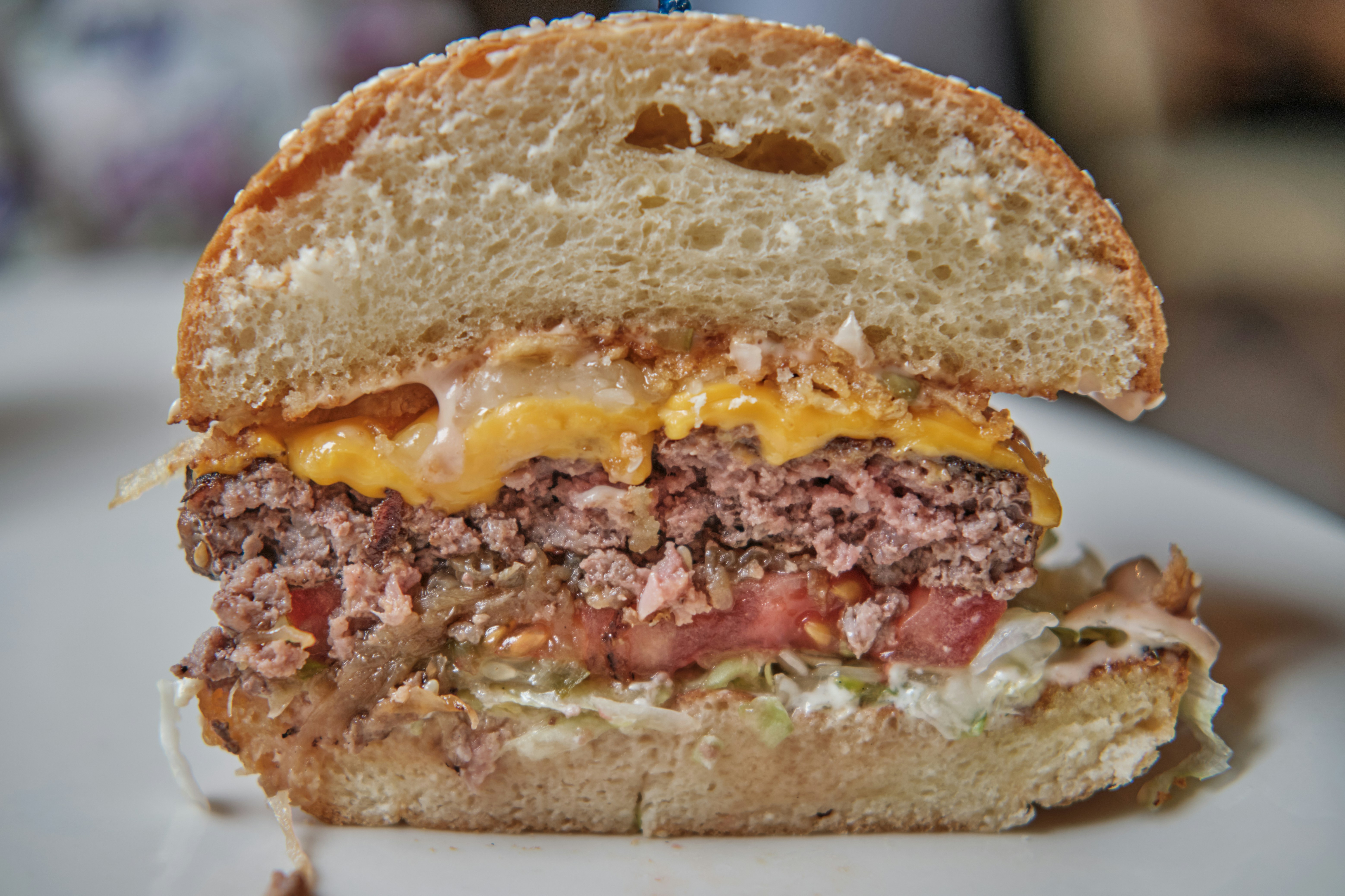 Cross-section of a mouthwatering burger showcasing layers of beef, cheese, and fresh vegetables. Perfectly assembled for a delicious bite.