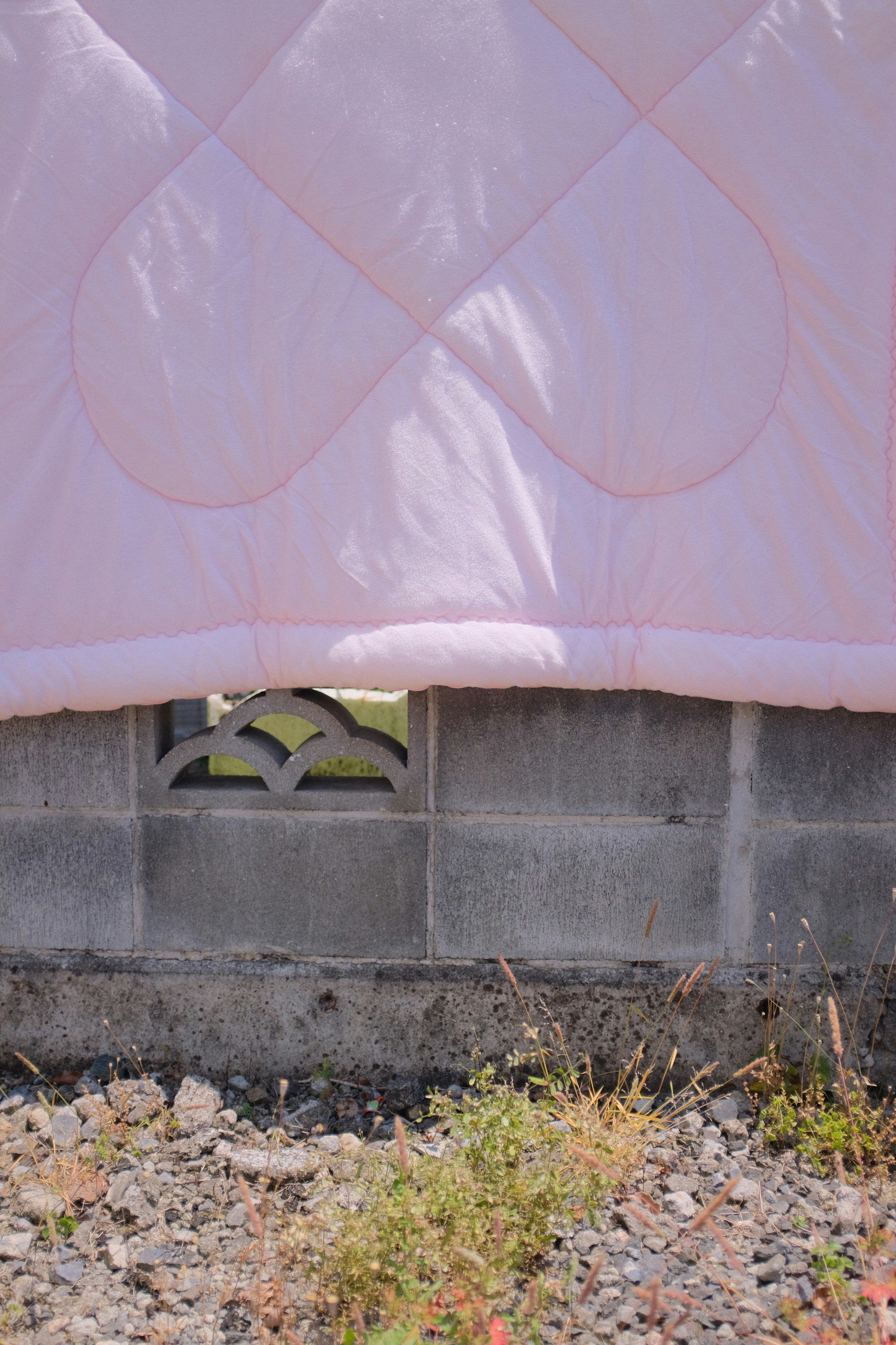 Pastel Quilt Over Concrete: Soft Texture Meets Rugged Wall