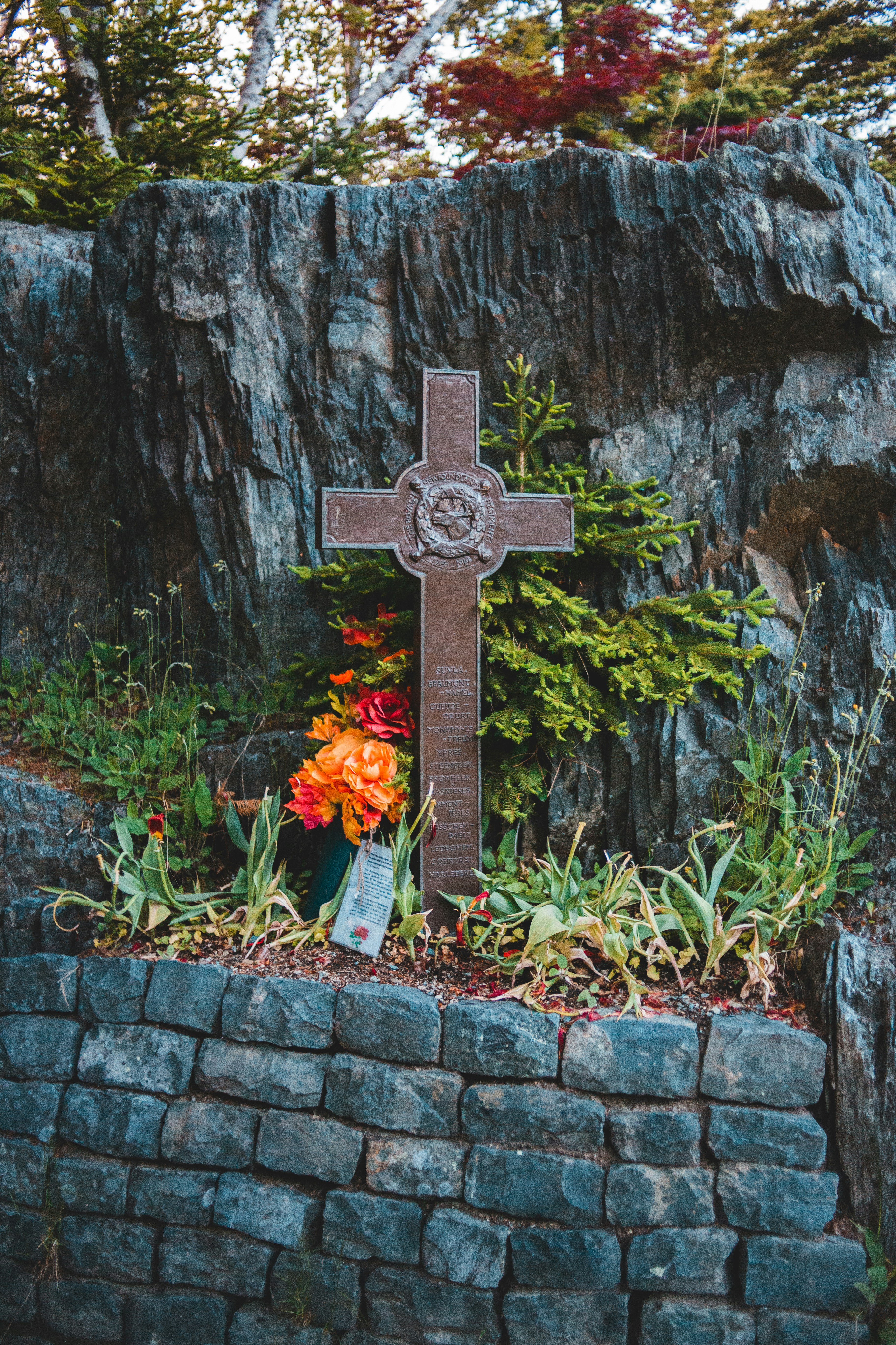 Cruciform Memorial Framed by Granite Backdrop and Autumn Blooms
