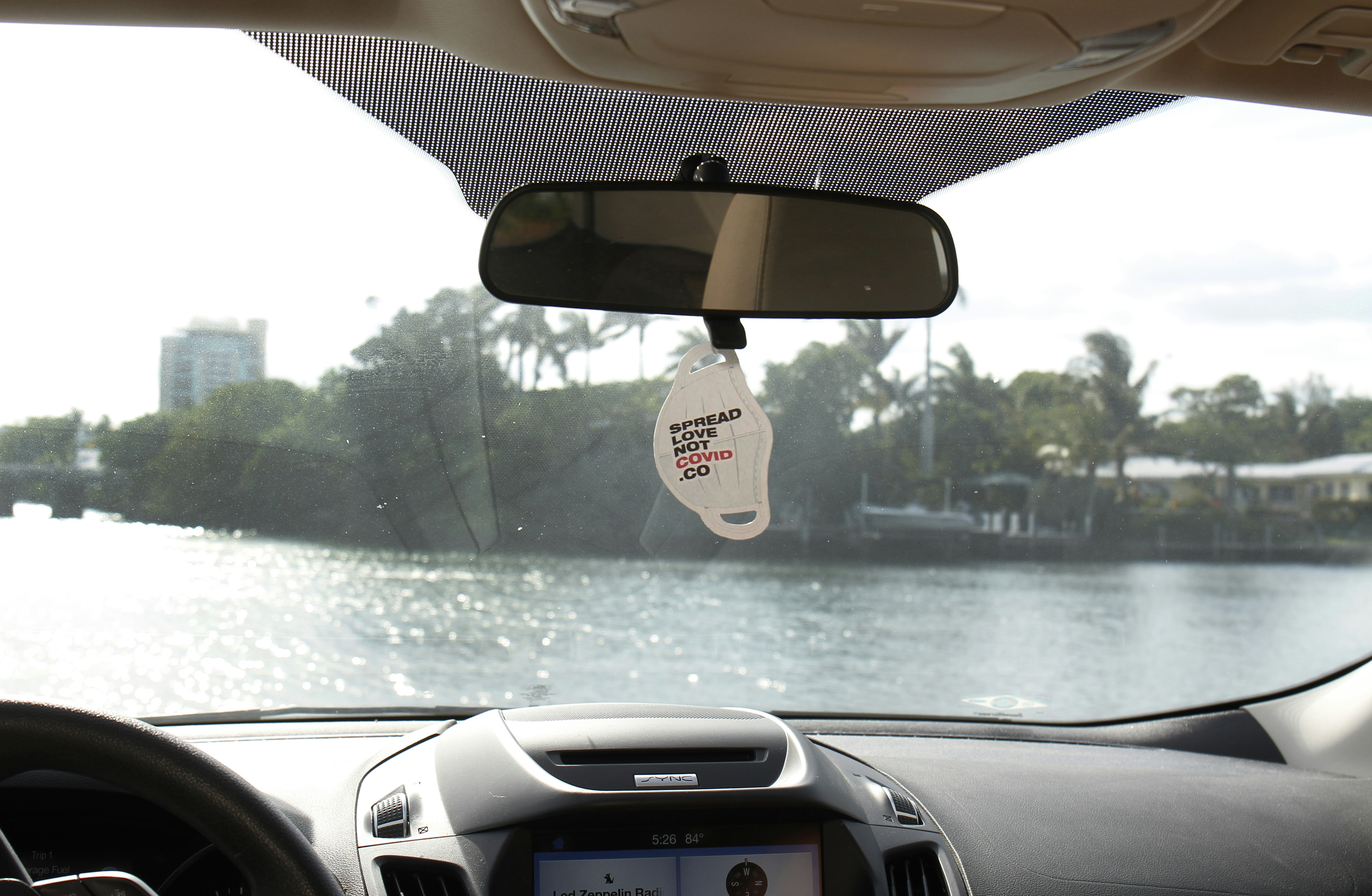 Rearview Mirror Reflections Over a Waterfront Drive