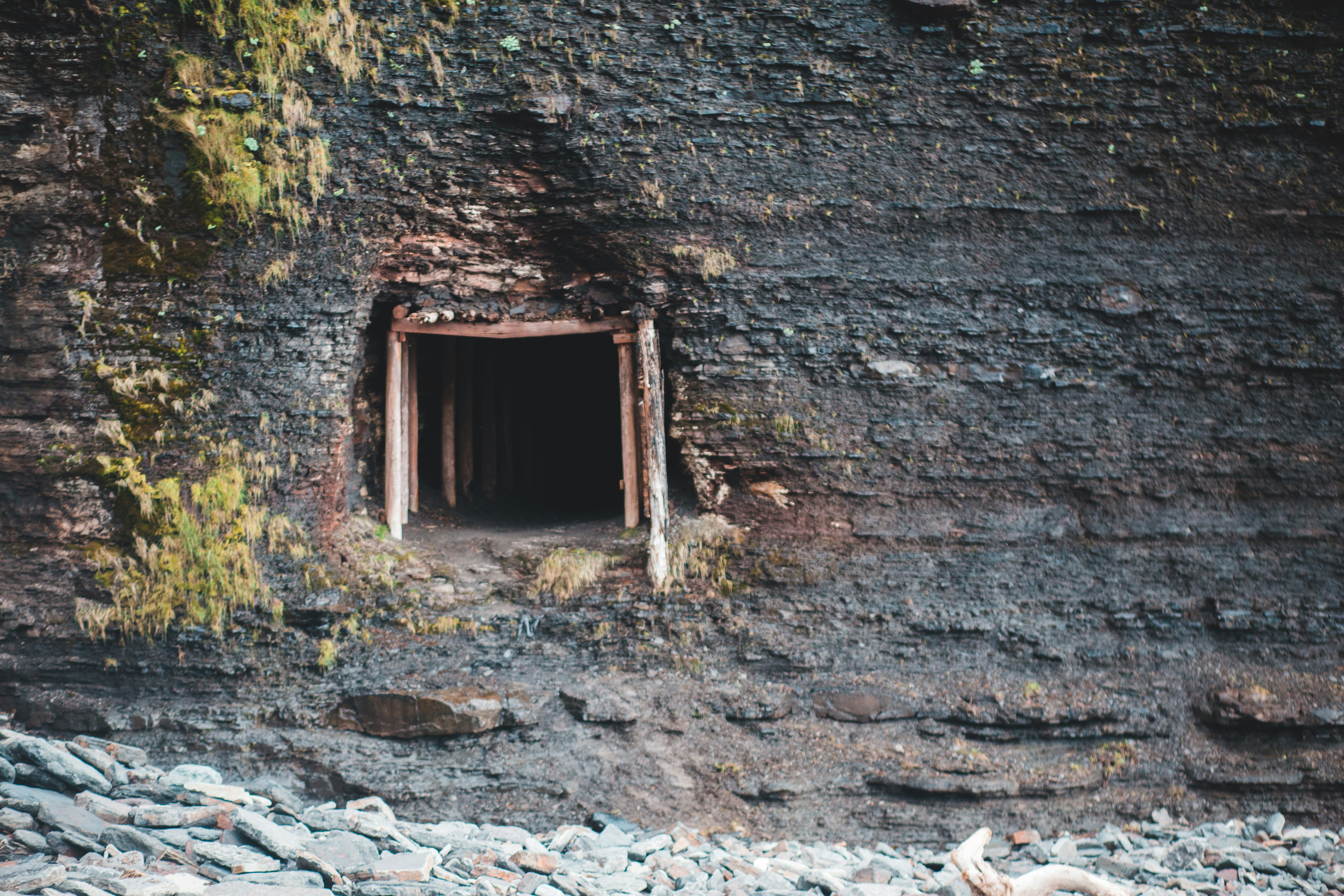 Dark Tunnel in Moss-Capped Cliff Face