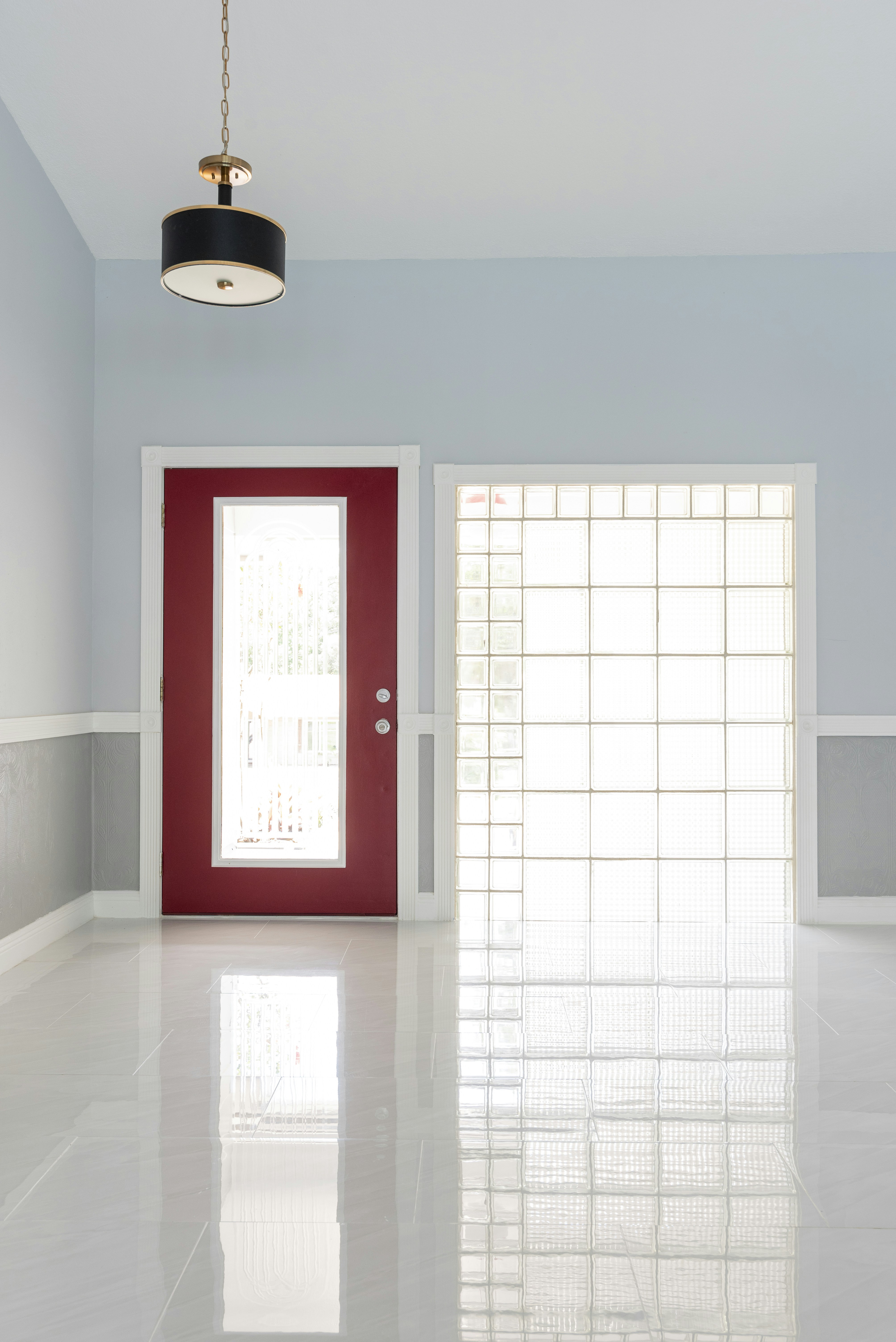 Crimson Door in a Pale-Blue Foyer: Light Reflections on a Glossy White Floor
