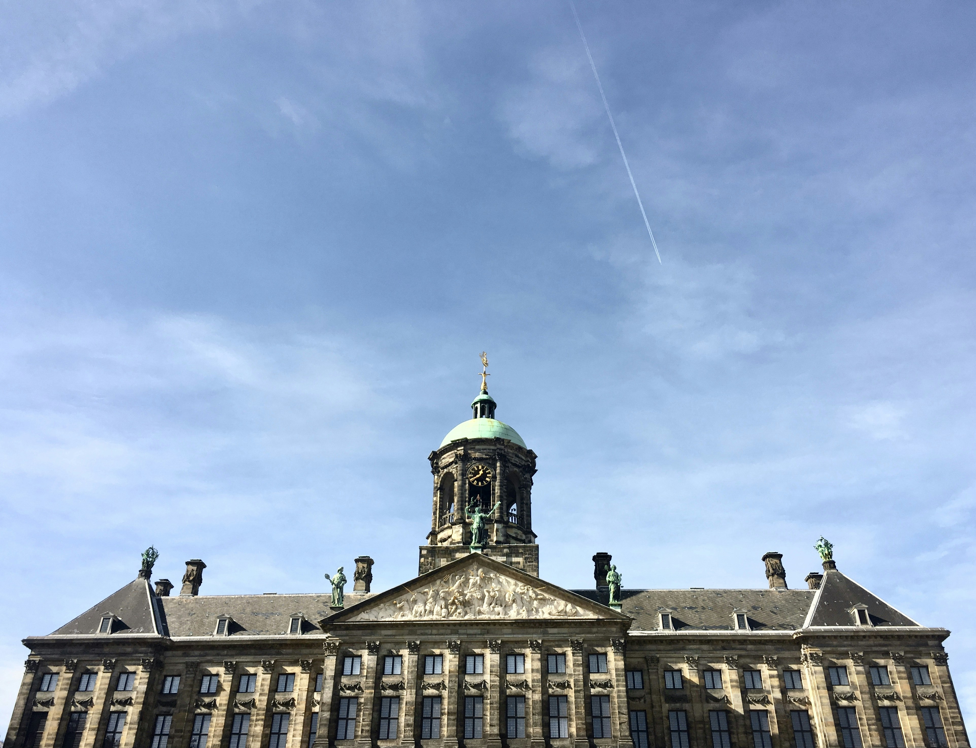 Historic building with intricate architectural details and a prominent clock tower, set against a bright blue sky.