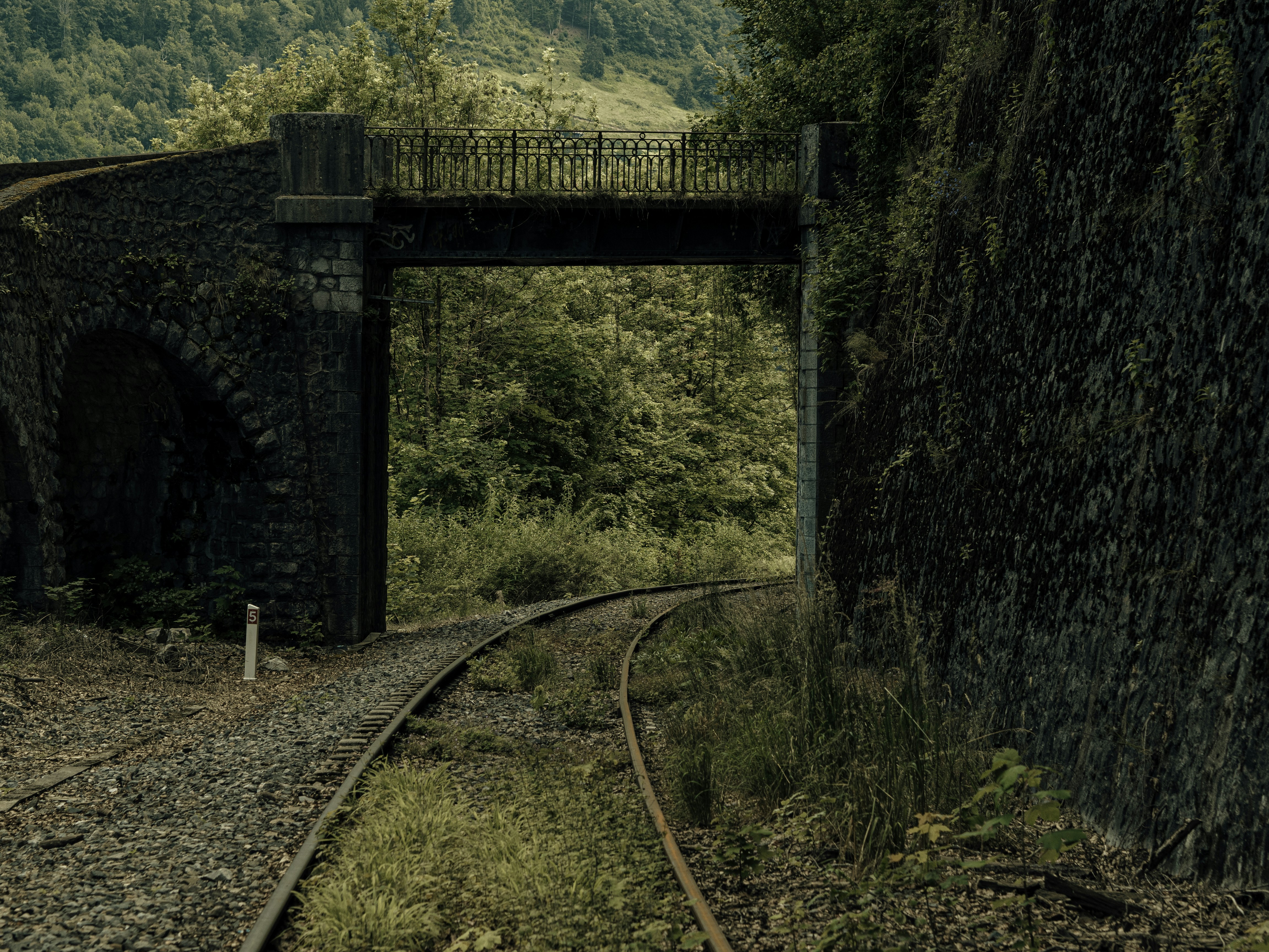 Rails Curve Beneath a Weathered Stone Bridge