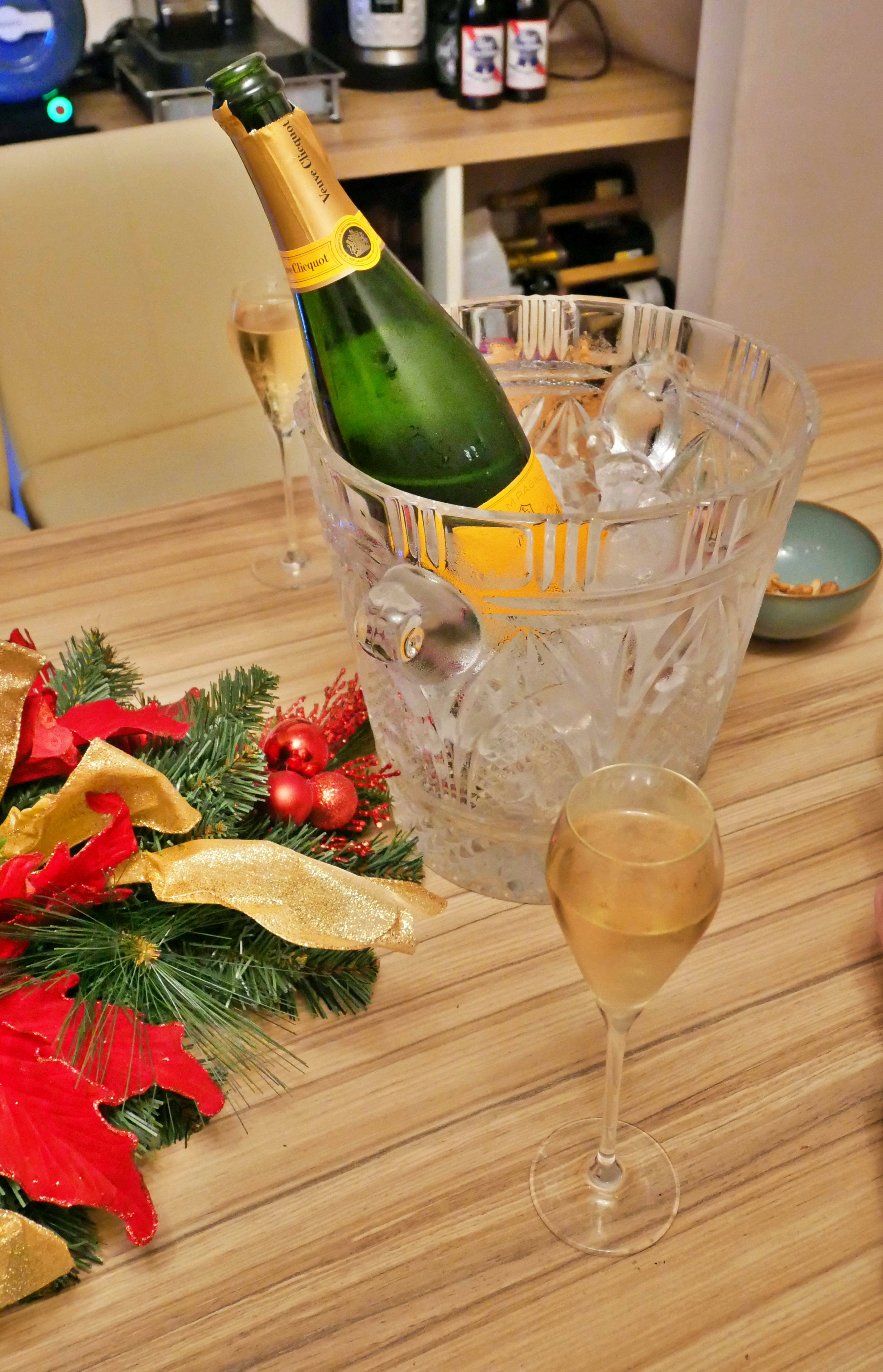 Chilled champagne bottle nestled in an ice bucket surrounded by festive decorations. A glass of sparkling wine awaits nearby.