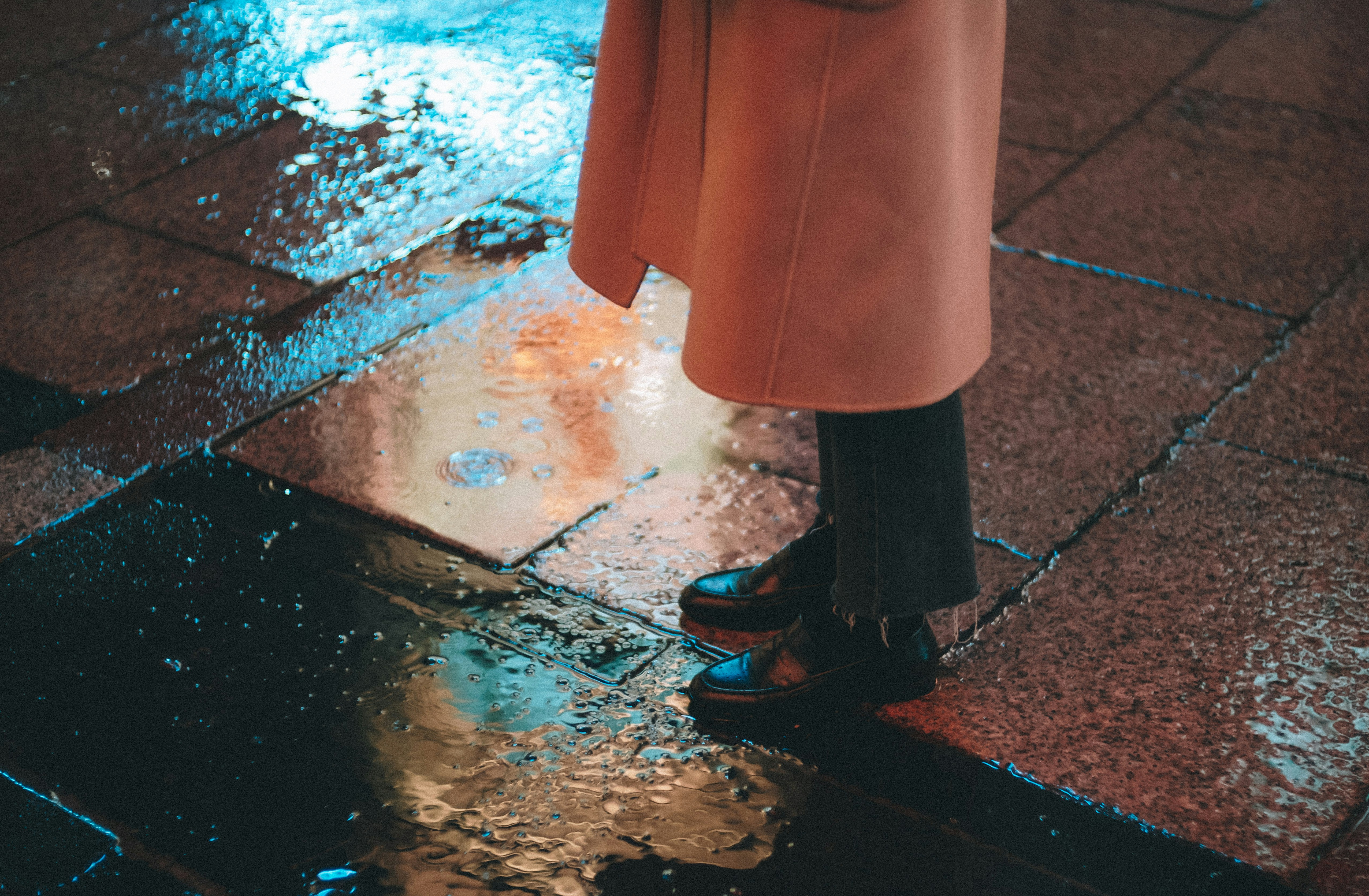 a person standing on a wet sidewalk in the rain