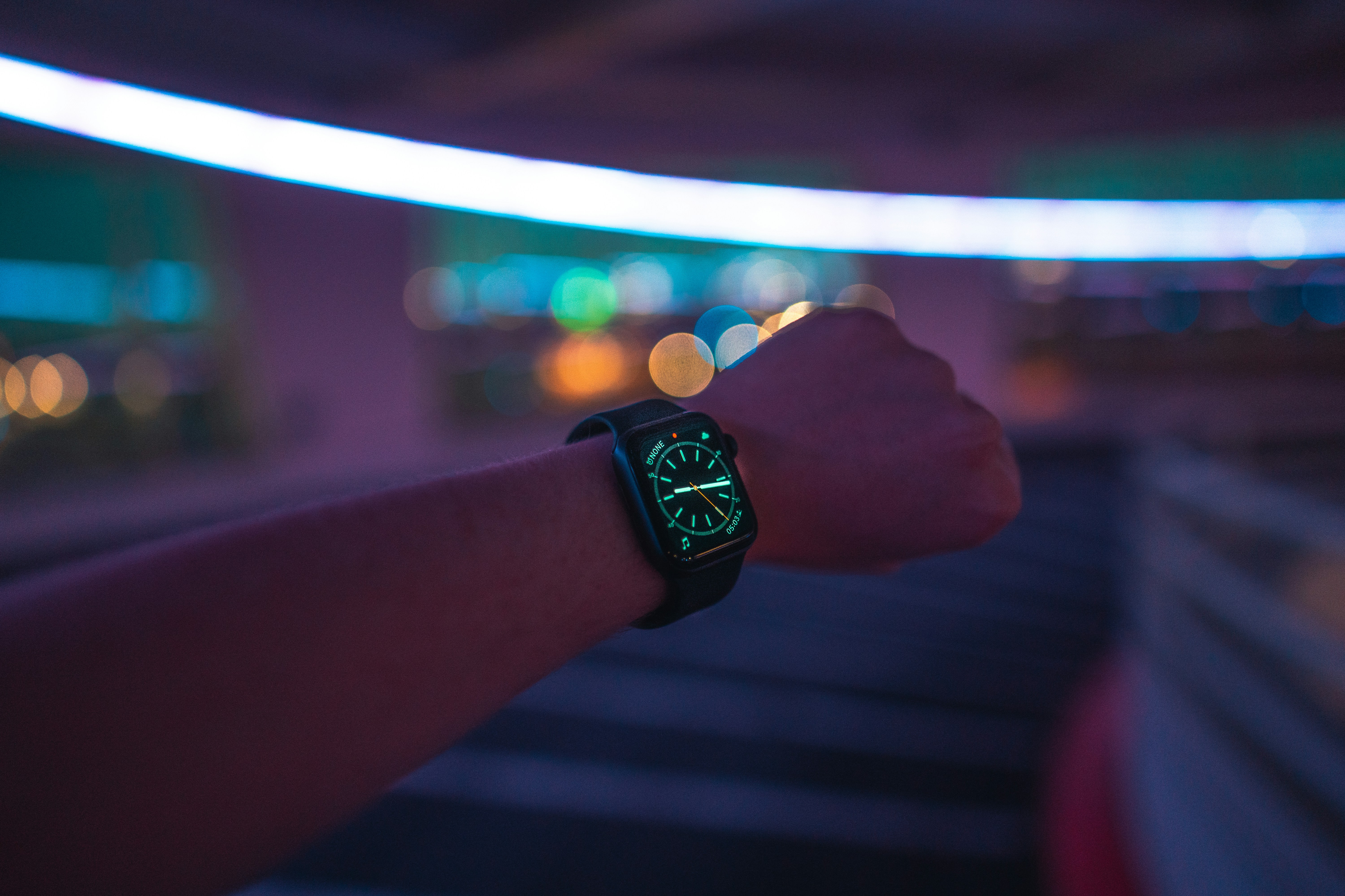 Neon-lit wristwatch in a blurred urban evening