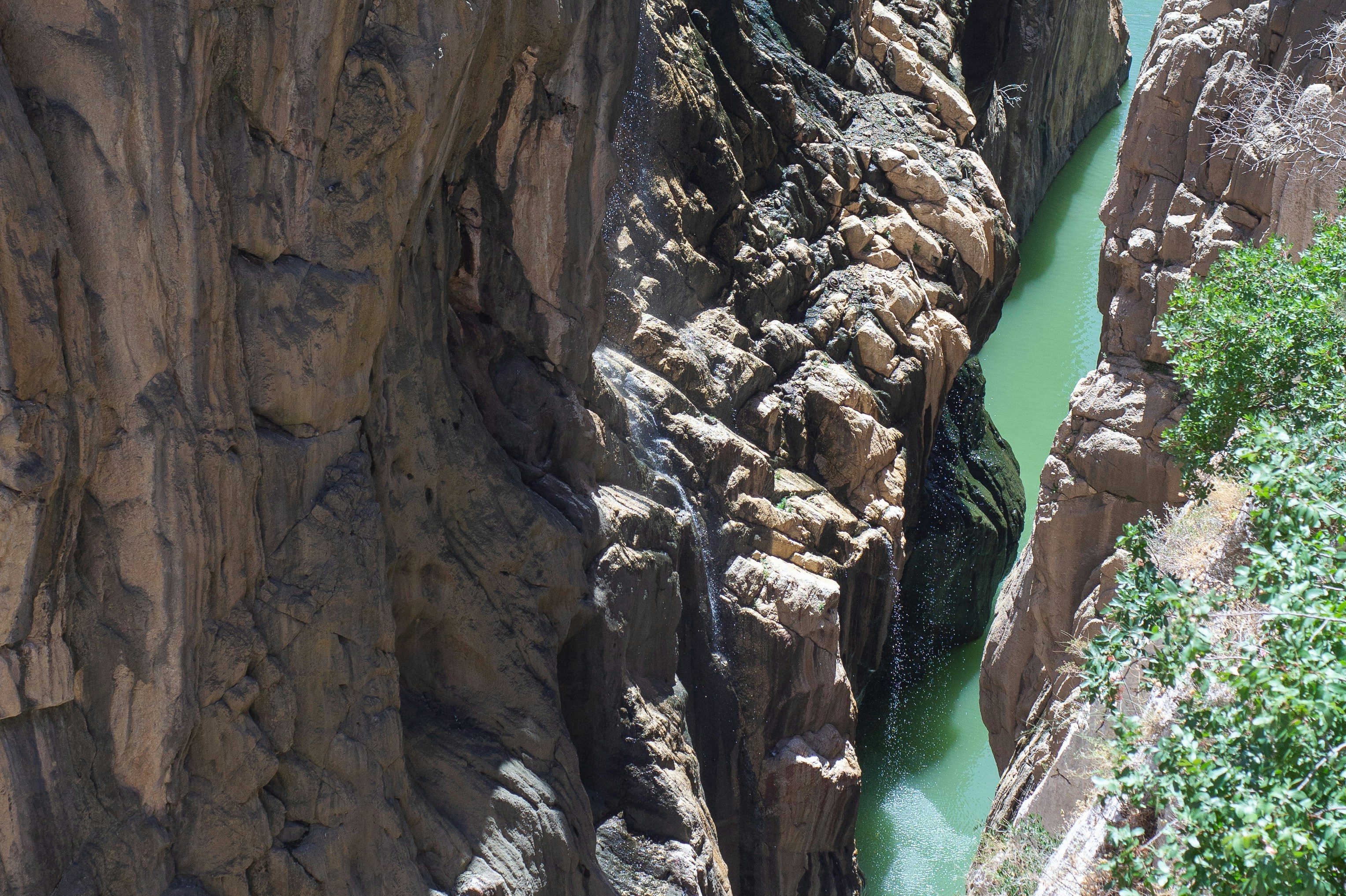 Steep rocky cliffs frame a narrow turquoise river winding through a lush landscape.