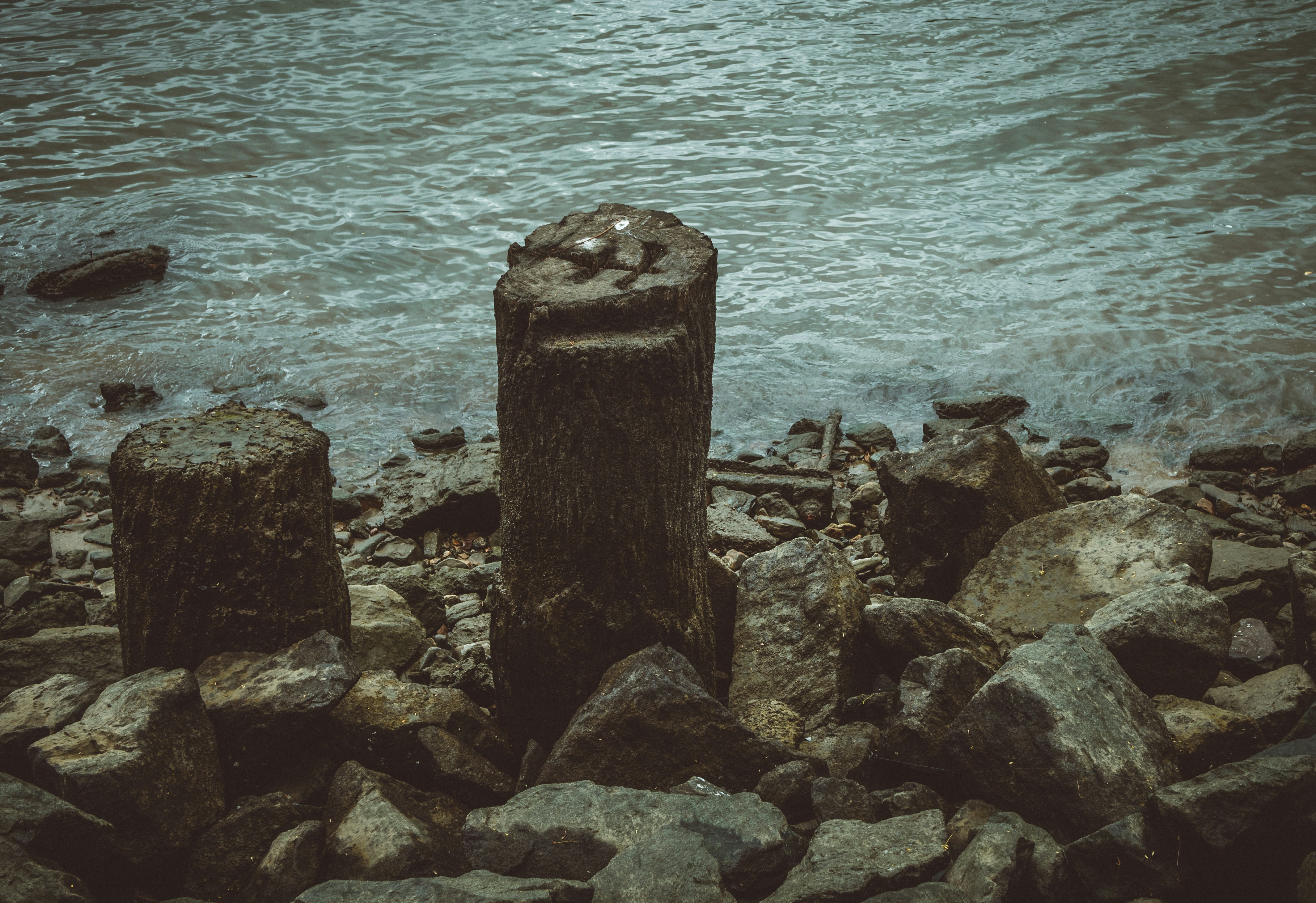 Black and gray rock formation near body of water during daytime photo ...