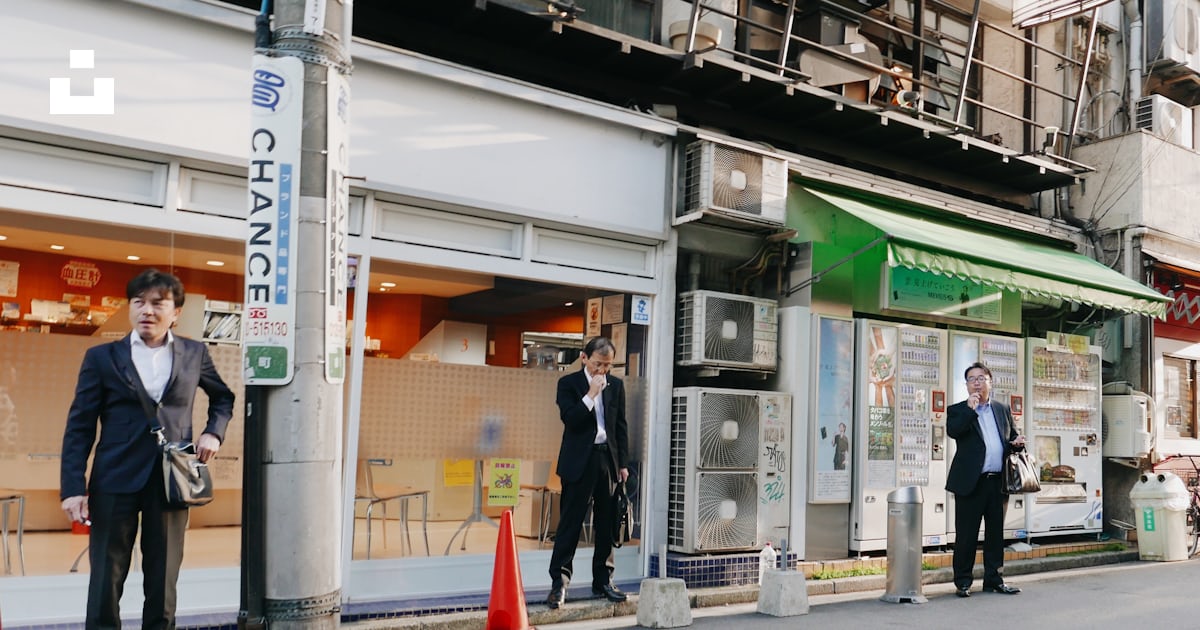 昼間、灰色のビルの近くに立つ黒いジャケットを着た男の写真 Unsplashの東京の無料画像