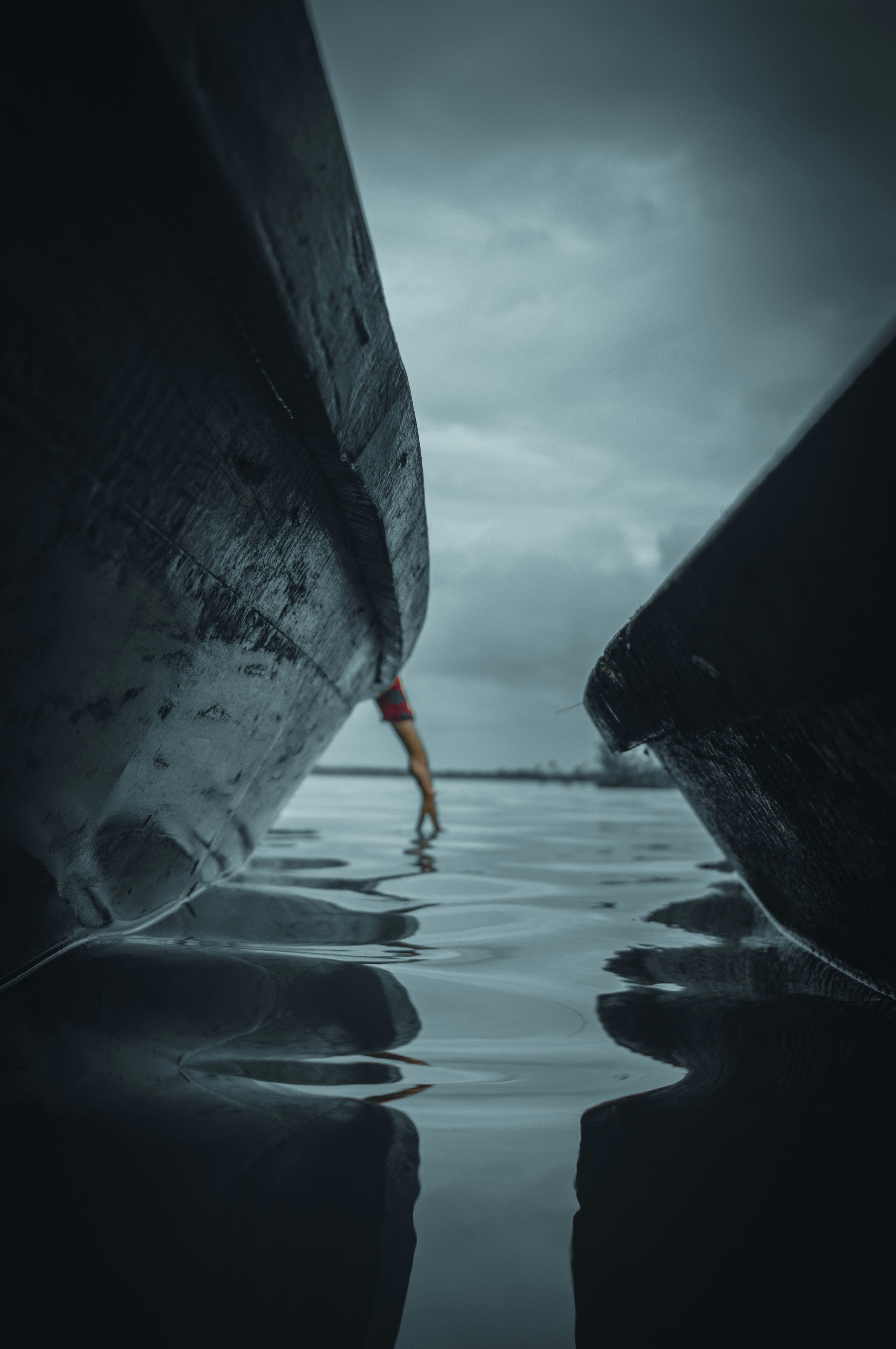Between Giants: A lone swimmer's silhouette carved by tidal shadows