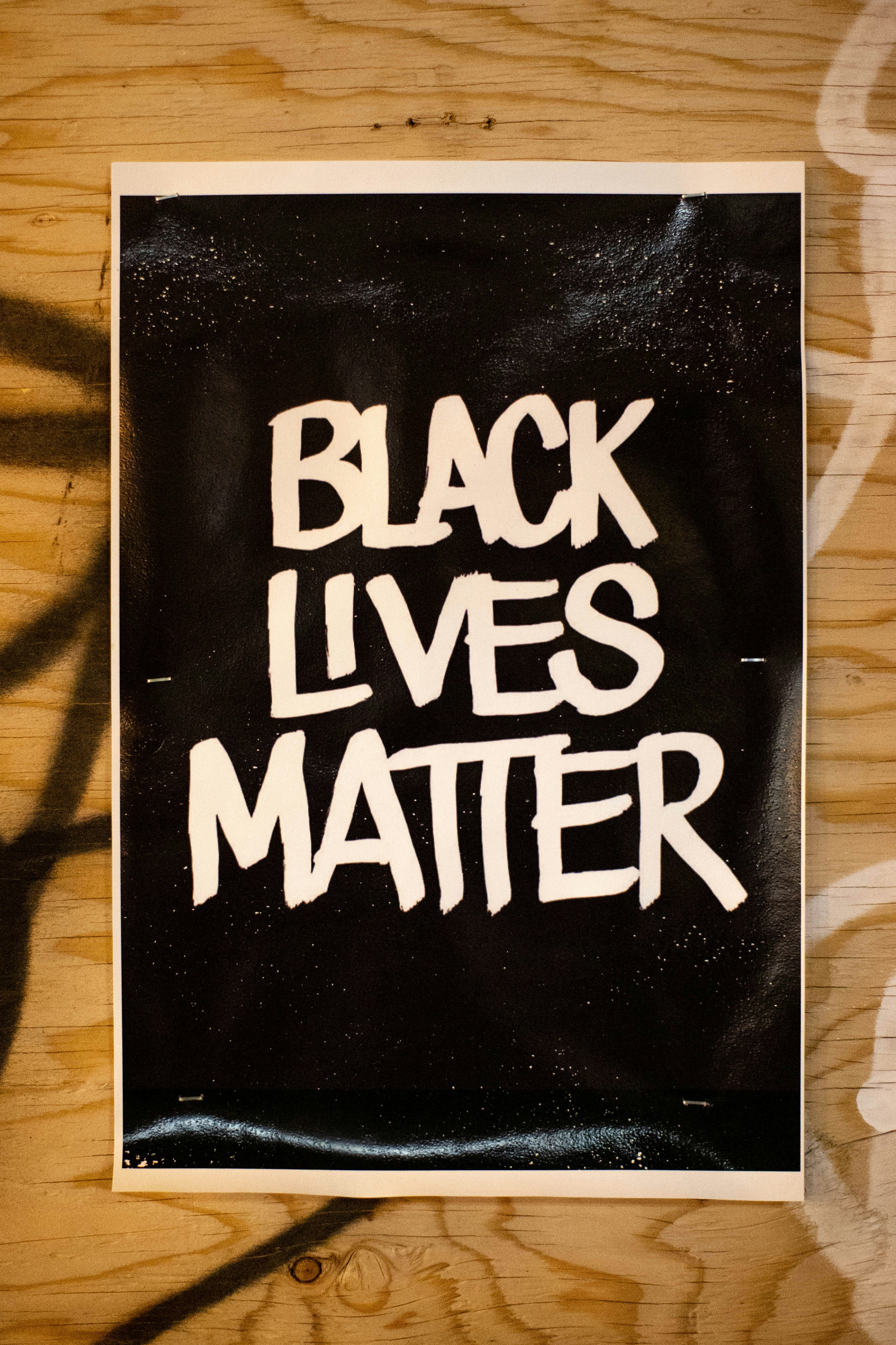 Black Lives Matter poster displayed against a textured wooden background.