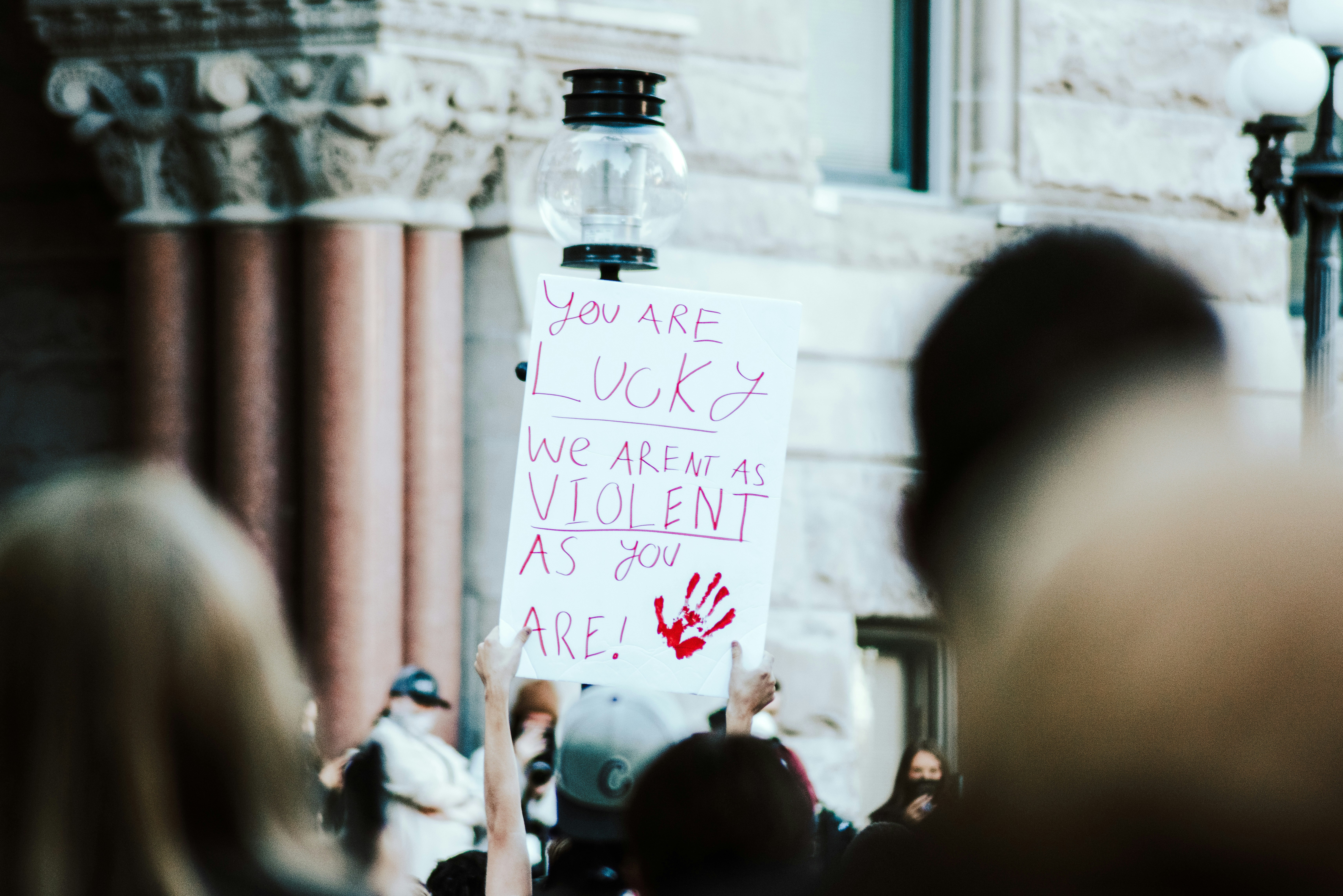 Protest sign with a red handprint, conveying a powerful message about violence and resilience during a demonstration.