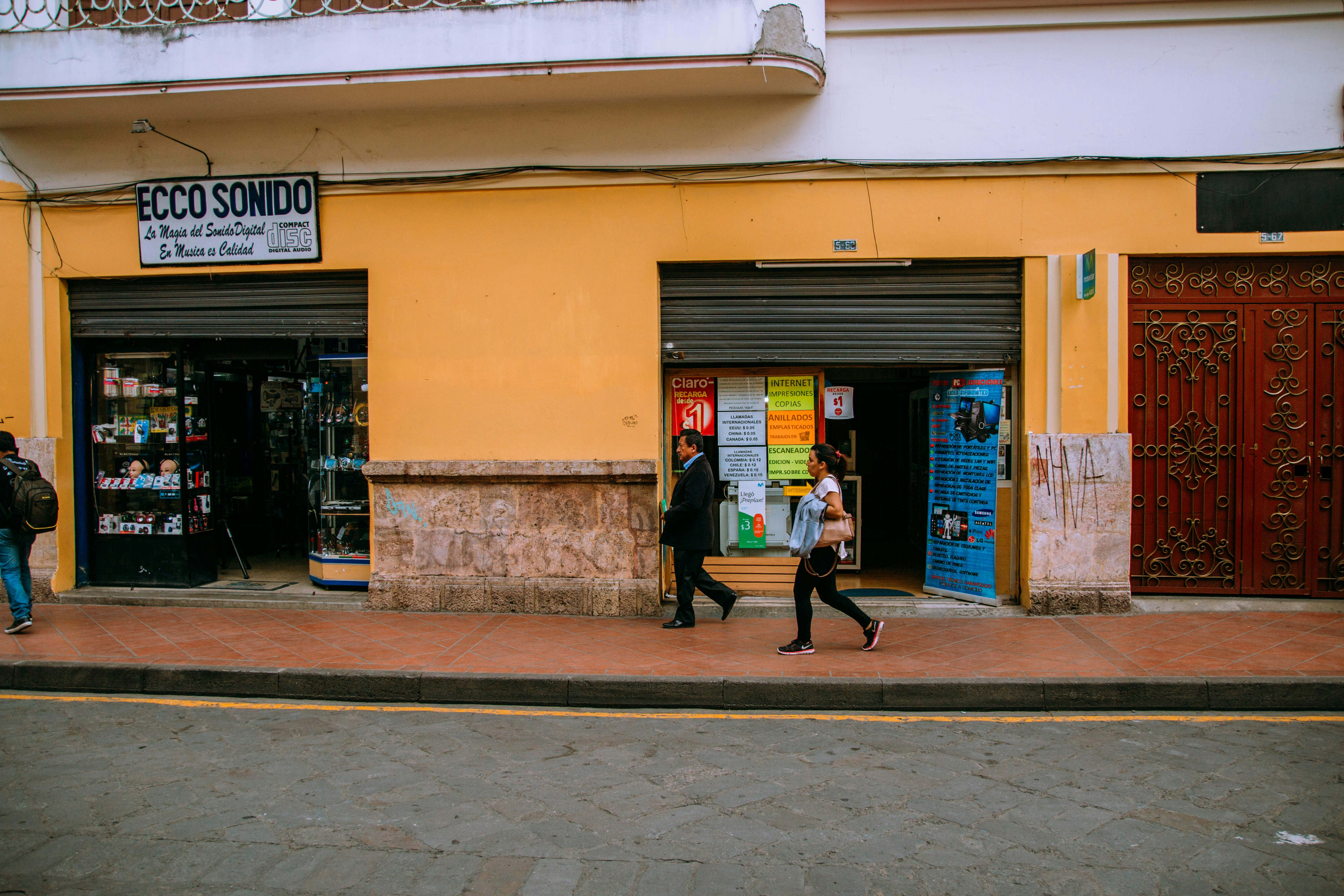 Sunlit Street Duet: Pedestrians Thread Through a Palette of Shops