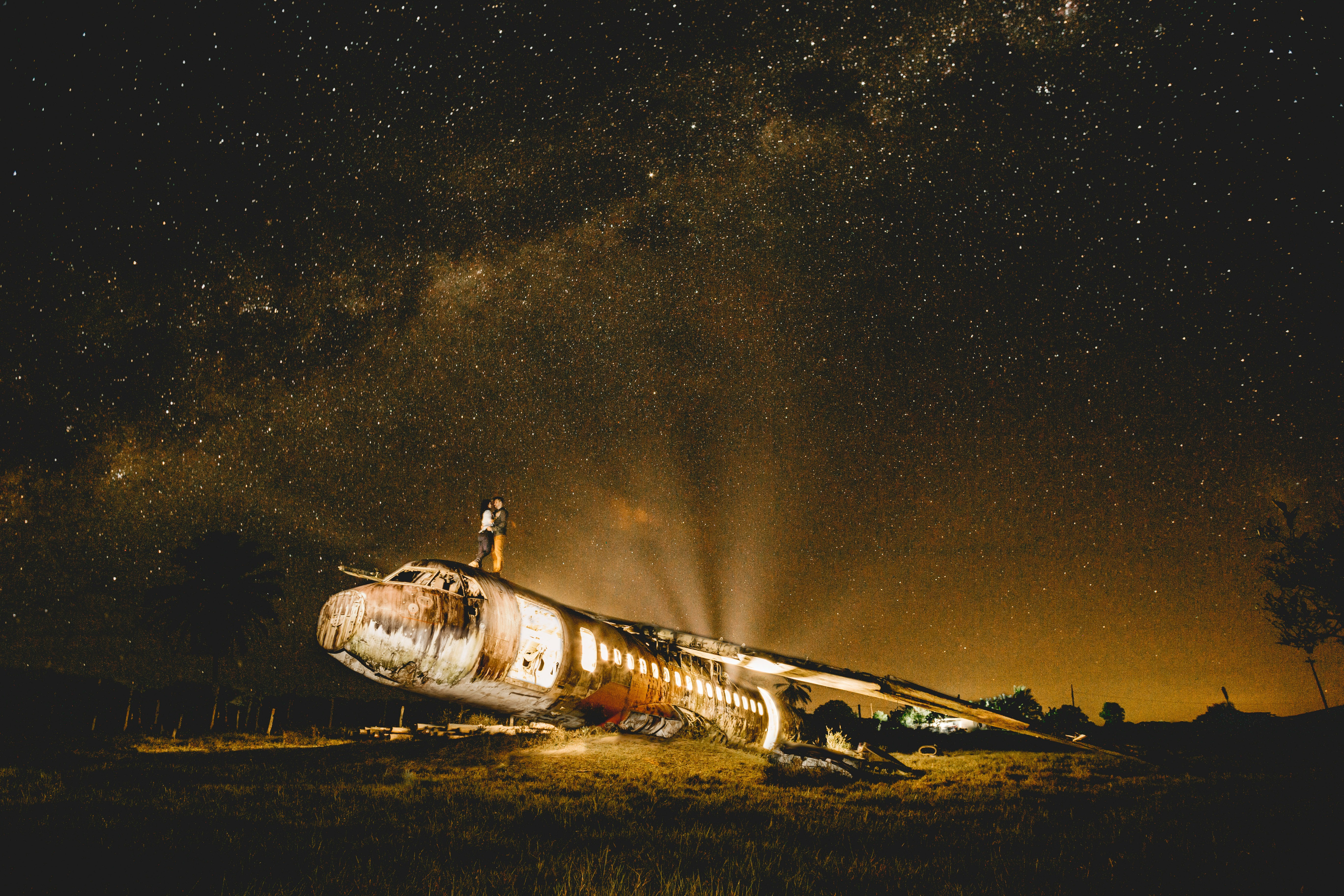 Star-Suffused Wreck: A lone climber atop a rusted railcar under a starry night