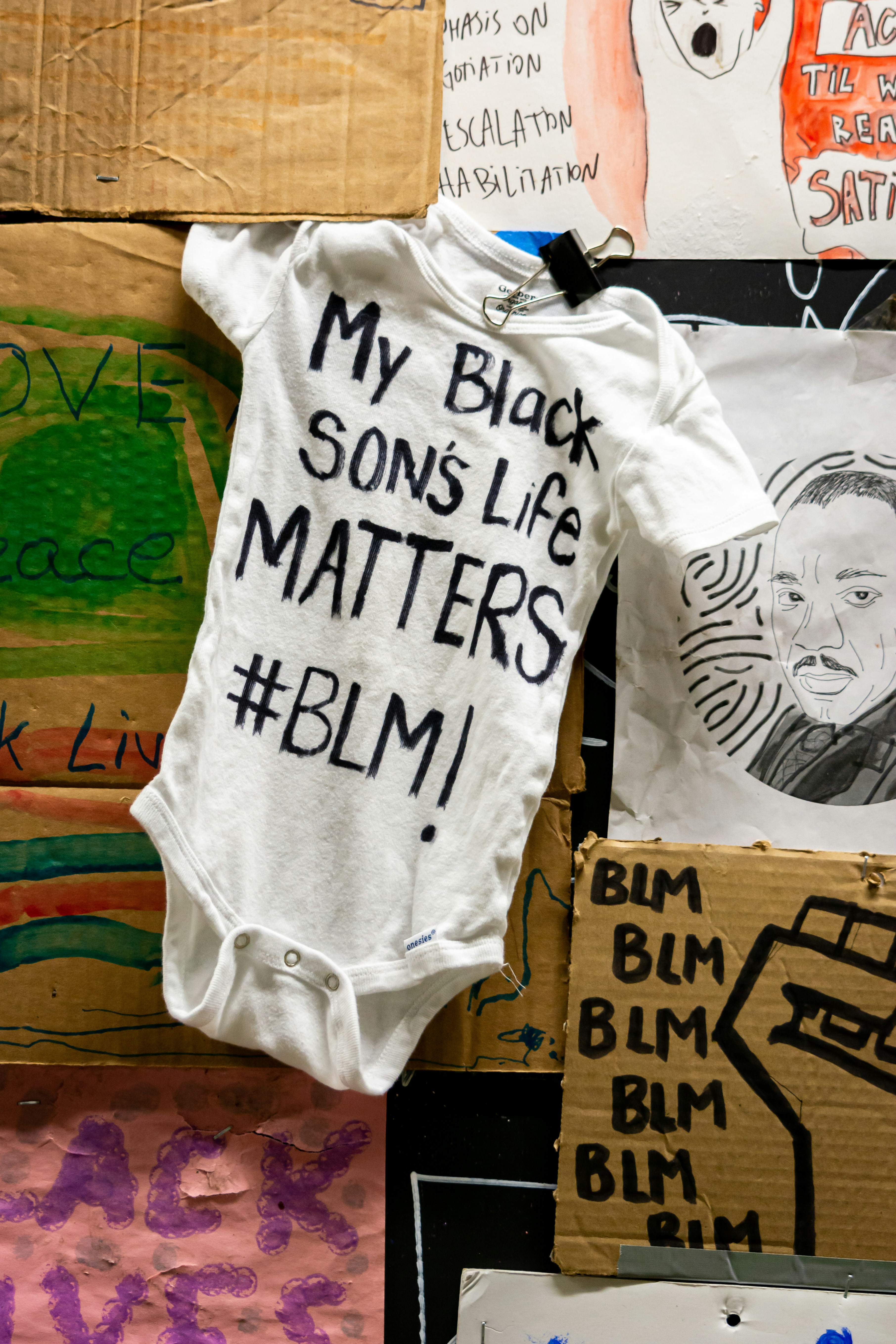 Message on Fabric: A White Onesie Centered Among Graffiti and Cardboard Art