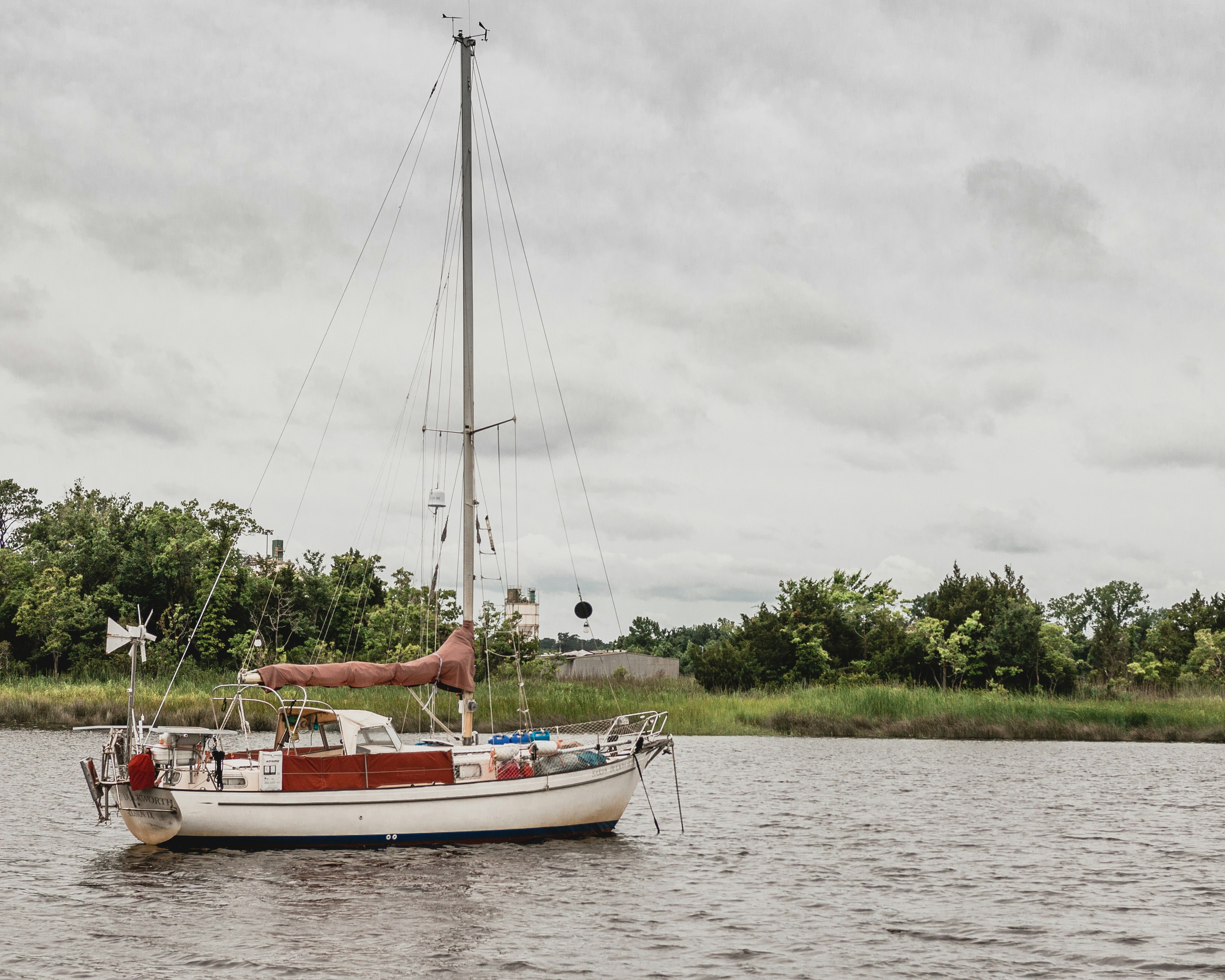 Mast and Mire: A Quiet Sailboat Anchored by a Marshside Shore