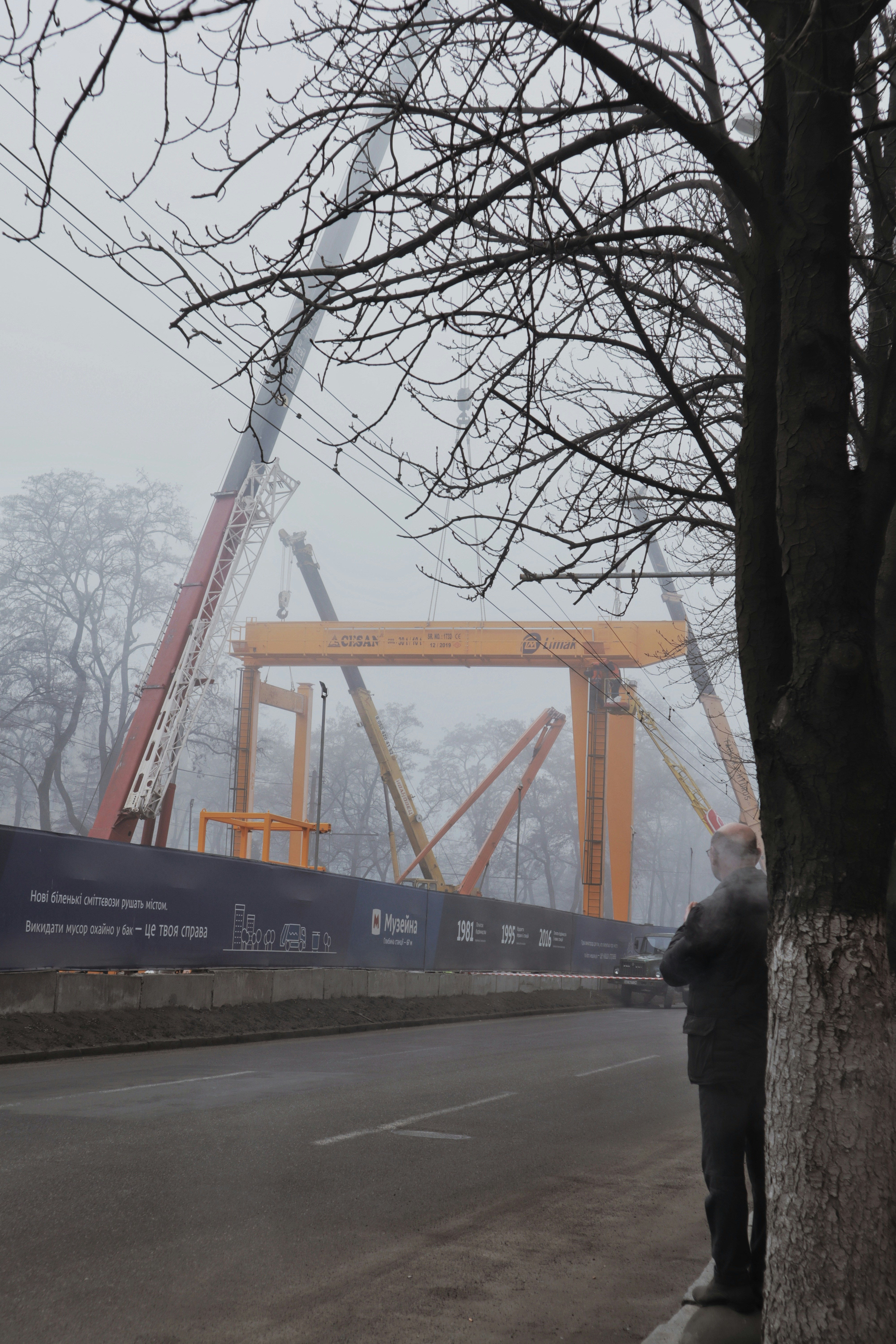 Lone Observer by a Fog-Shrouded Construction Yard