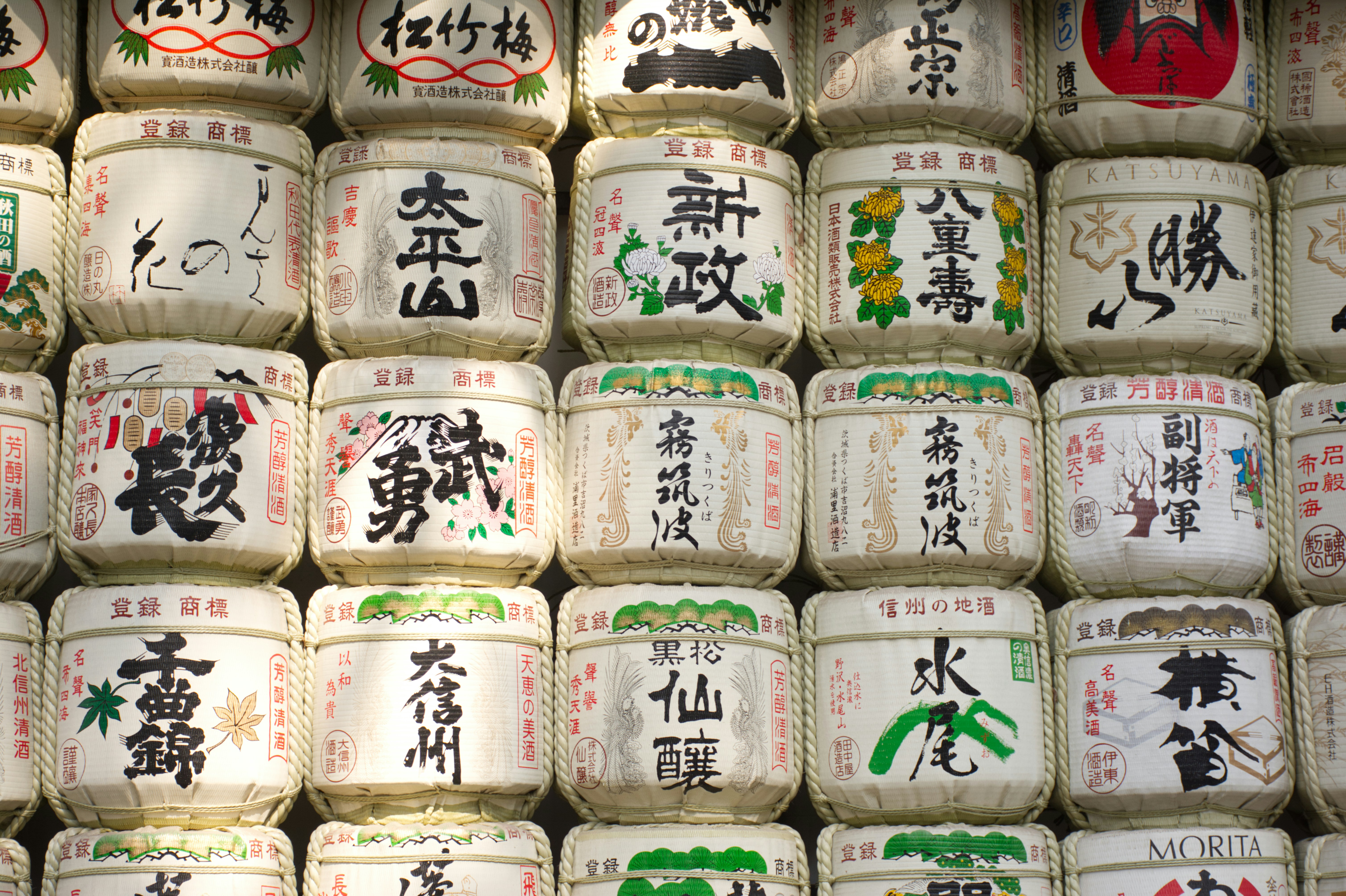 A vibrant arrangement of sake casks, each adorned with unique calligraphy and colorful designs, showcasing the artistry and culture of Japanese brewing.
