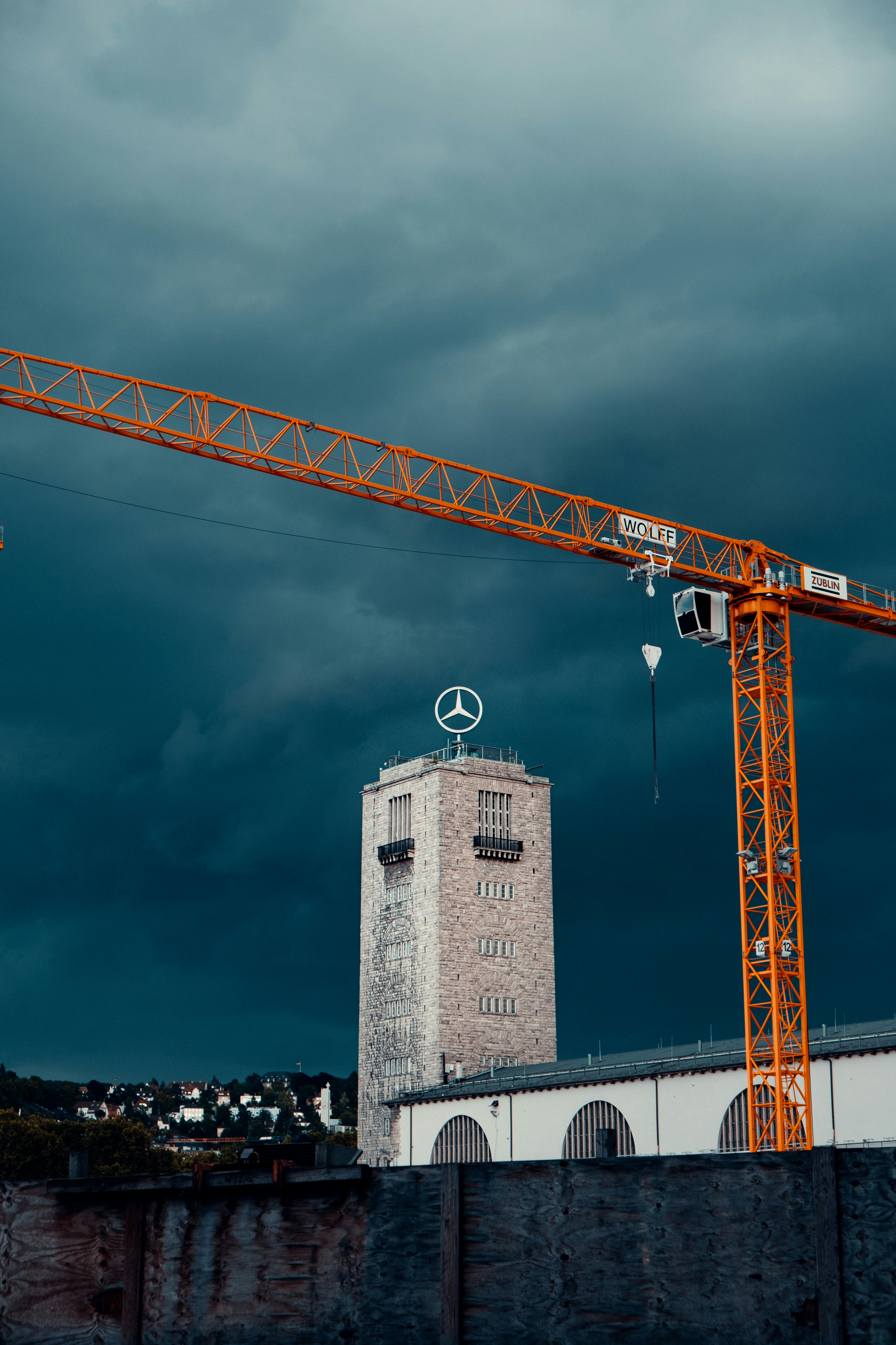 Crane Crown: A Mercedes Signaled by Weather Over Berlin's Concrete