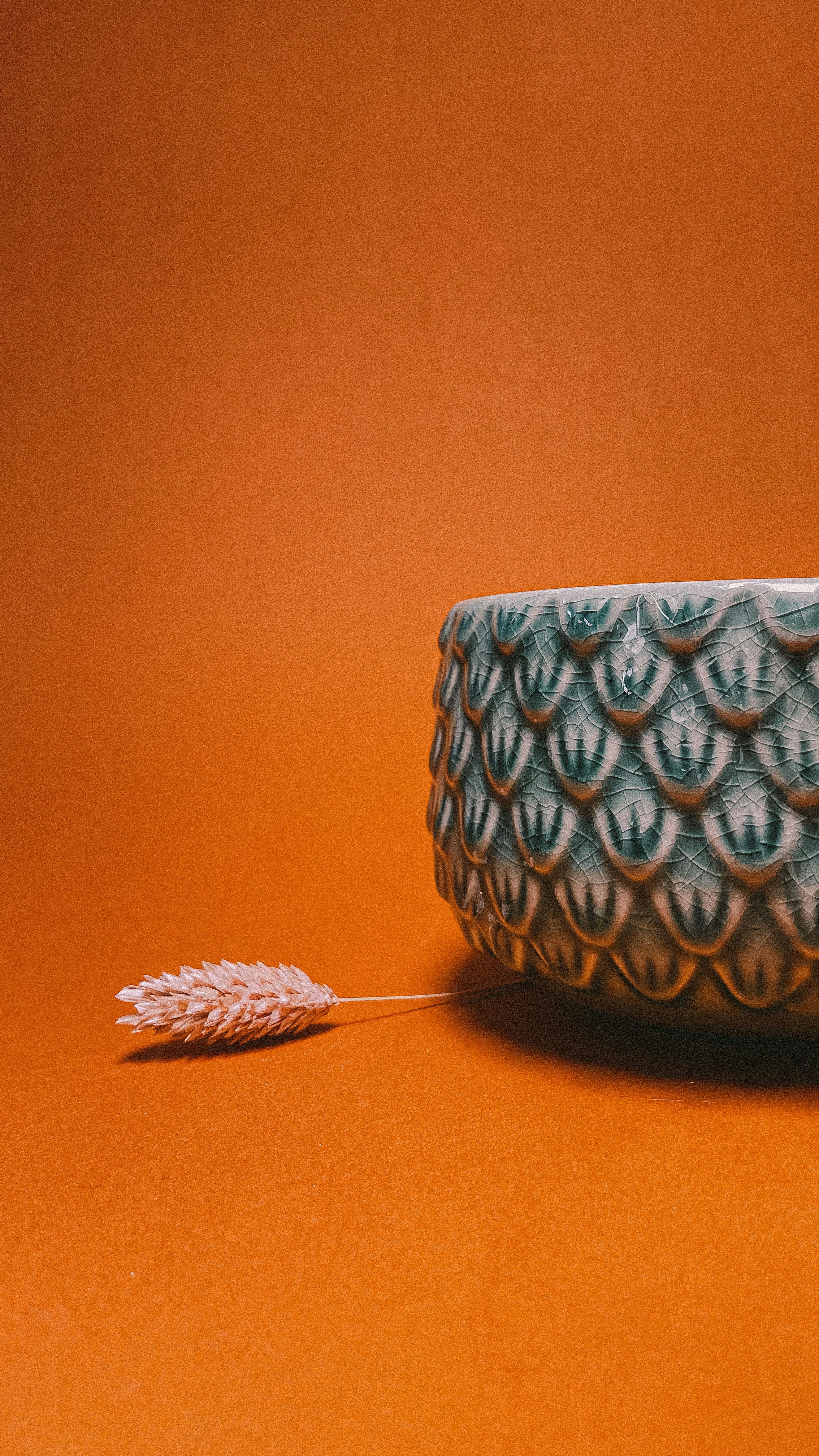 Minimalist still life: a teal textured bowl against a warm orange backdrop