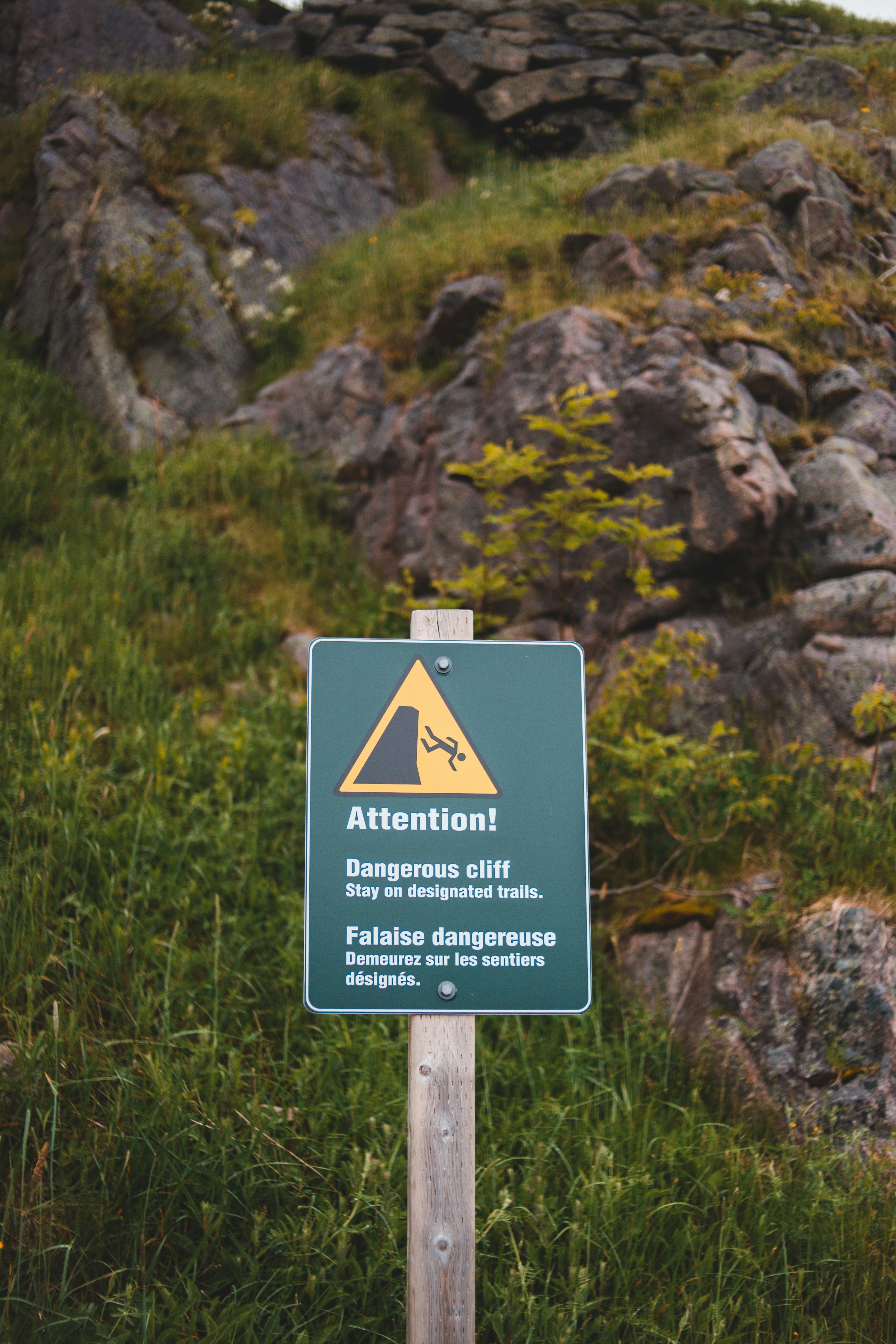 Warning from the Clifftop: A Sign Amid Rocks and Grass