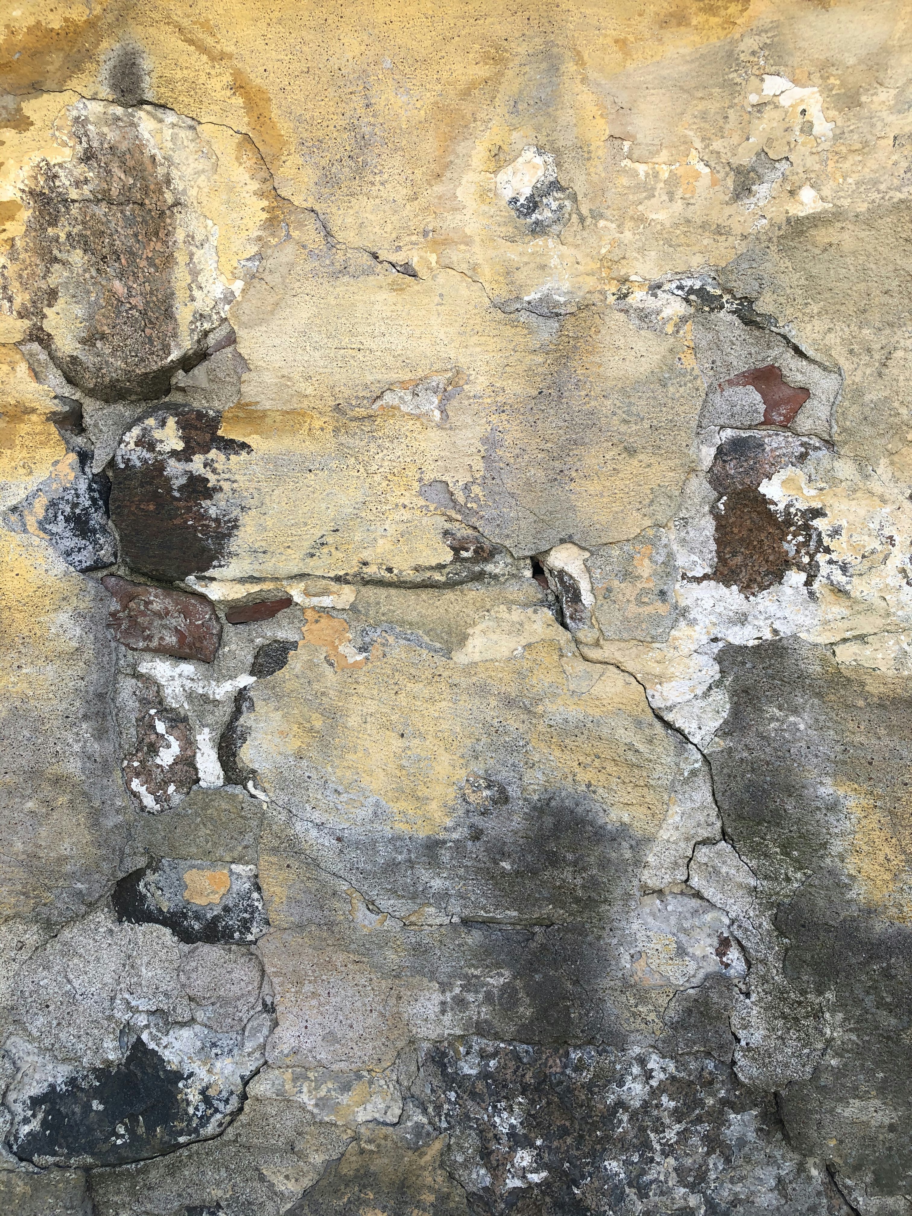 Cracked Echoes: Weathered Plaster and Faded Brick on a Sunlit Wall