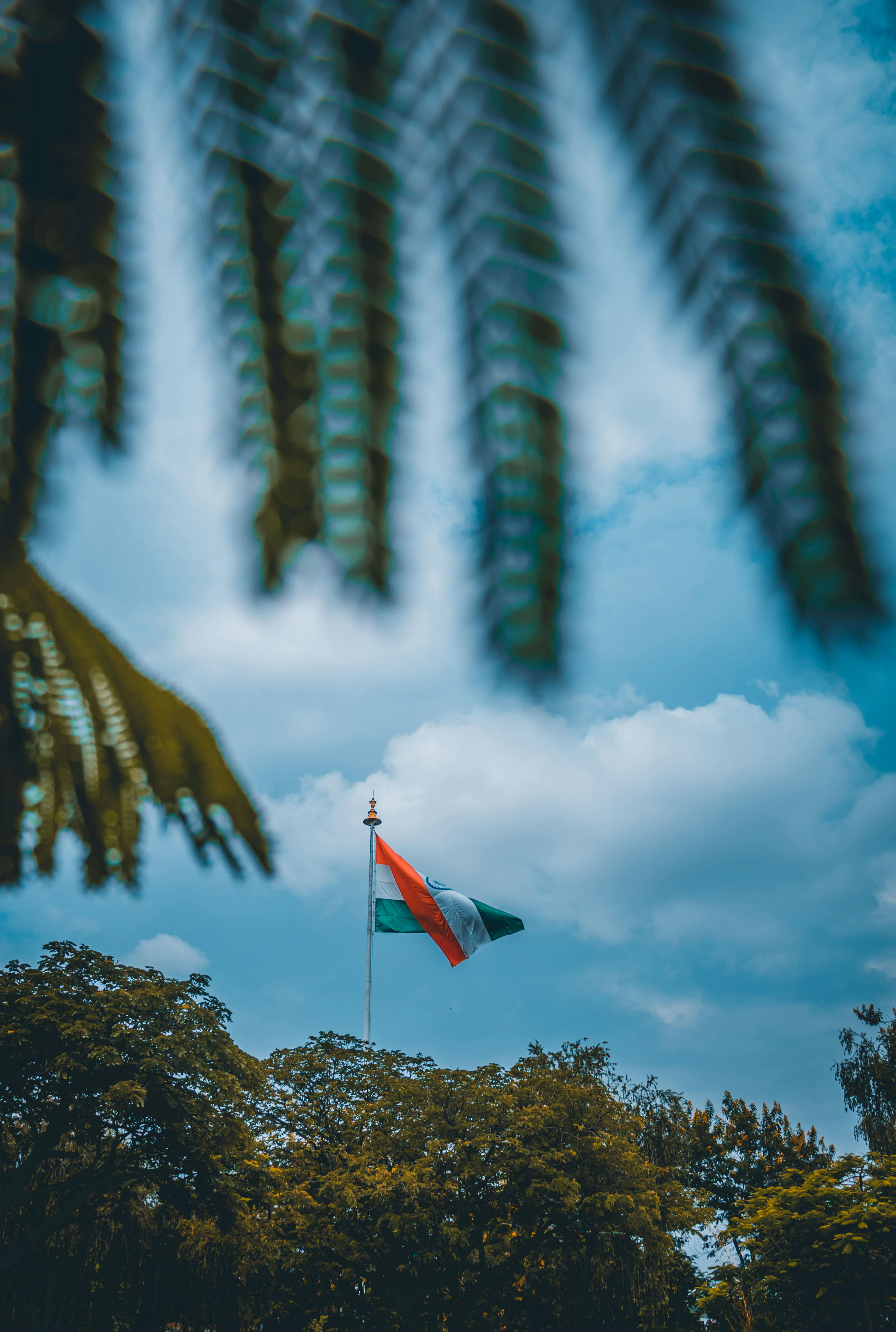 red white and blue flag on rocky ground under blue and white sunny cloudy sky during