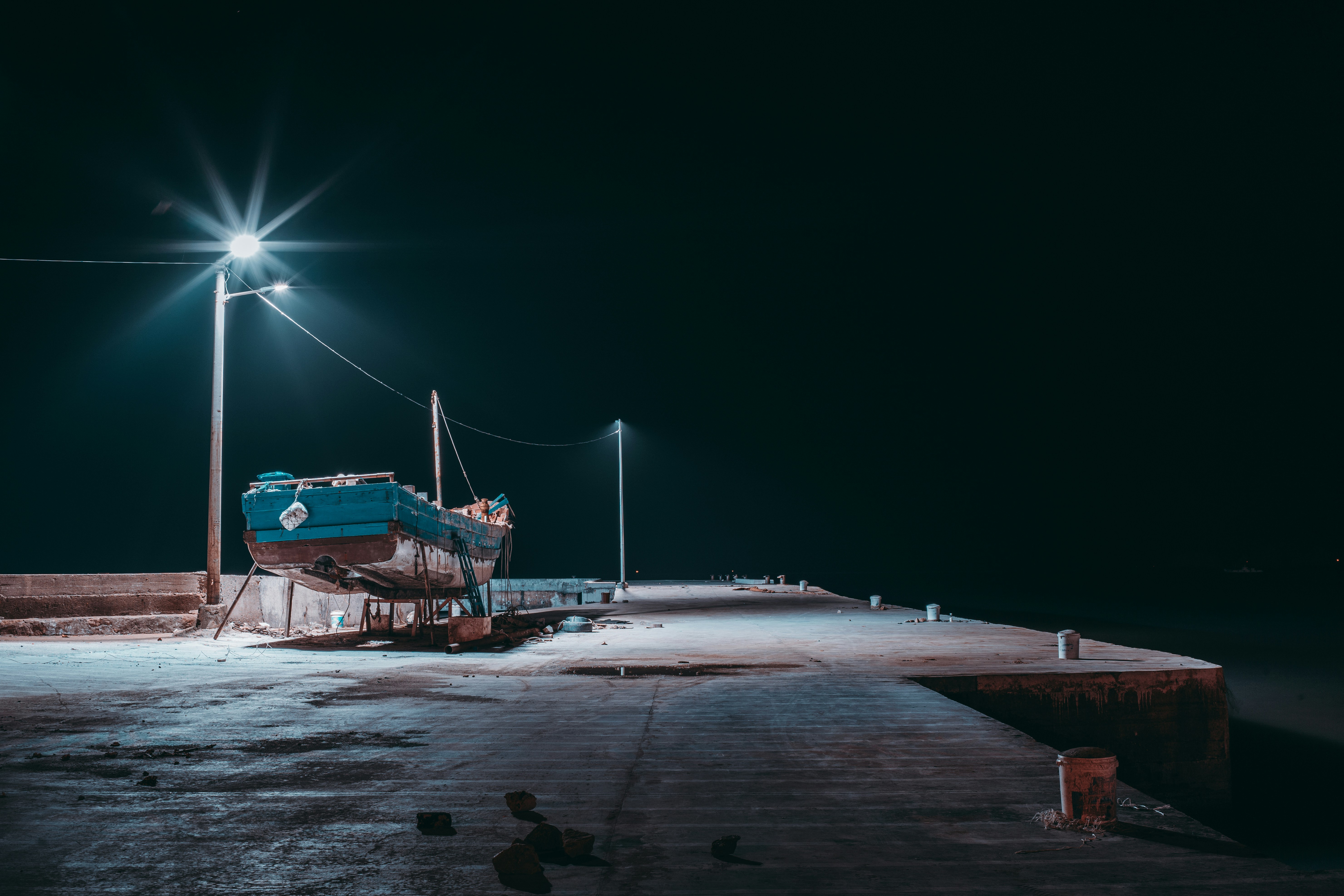 Glimmering Night Pier: Boat Resting Beneath a Lone Streetlamp