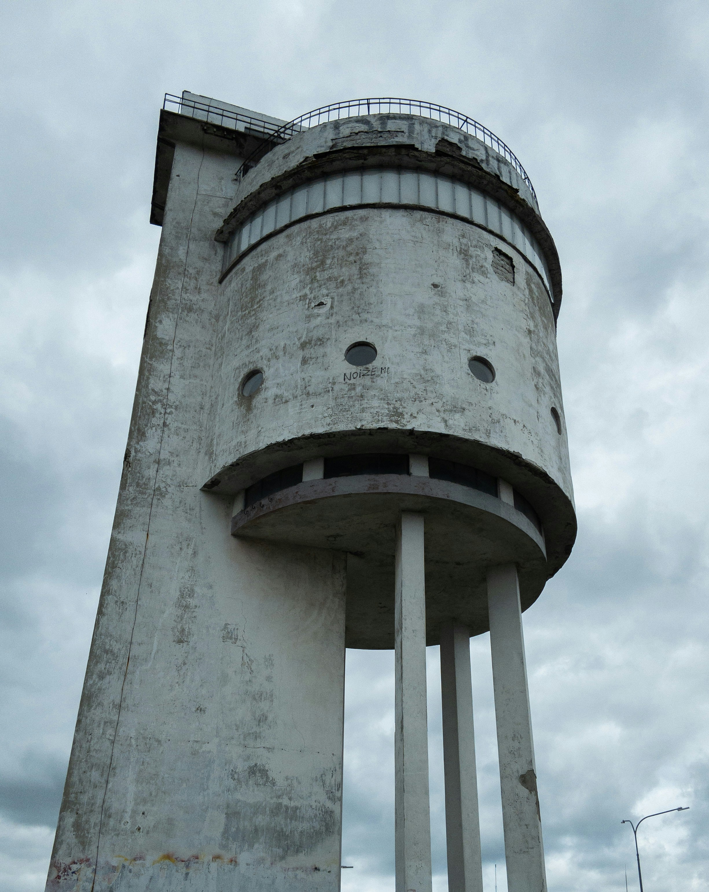 Circular Concrete Sentinel on Stilts Under a Cloudy Sky