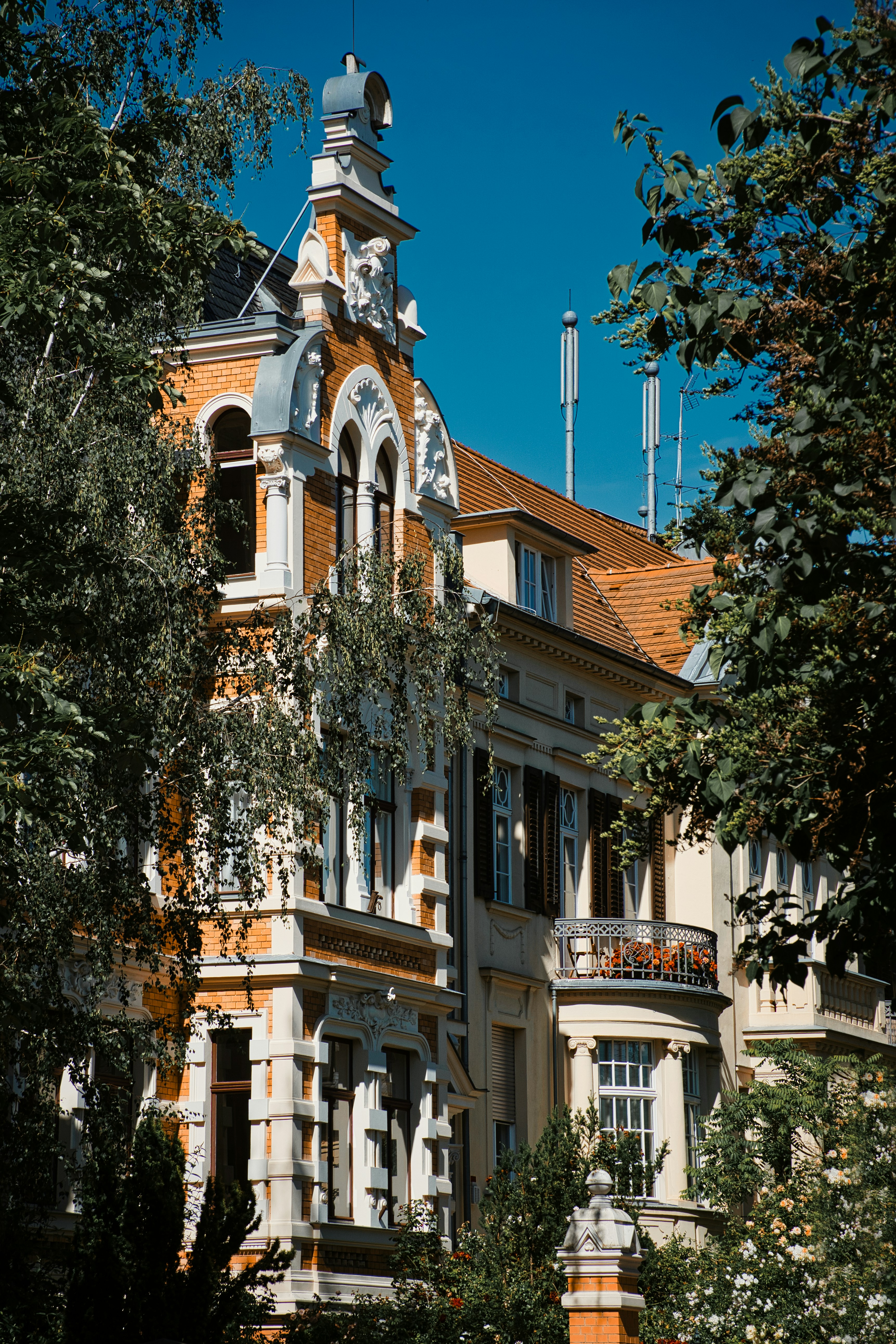 Historic building with intricate architectural details framed by lush greenery and a clear blue sky.