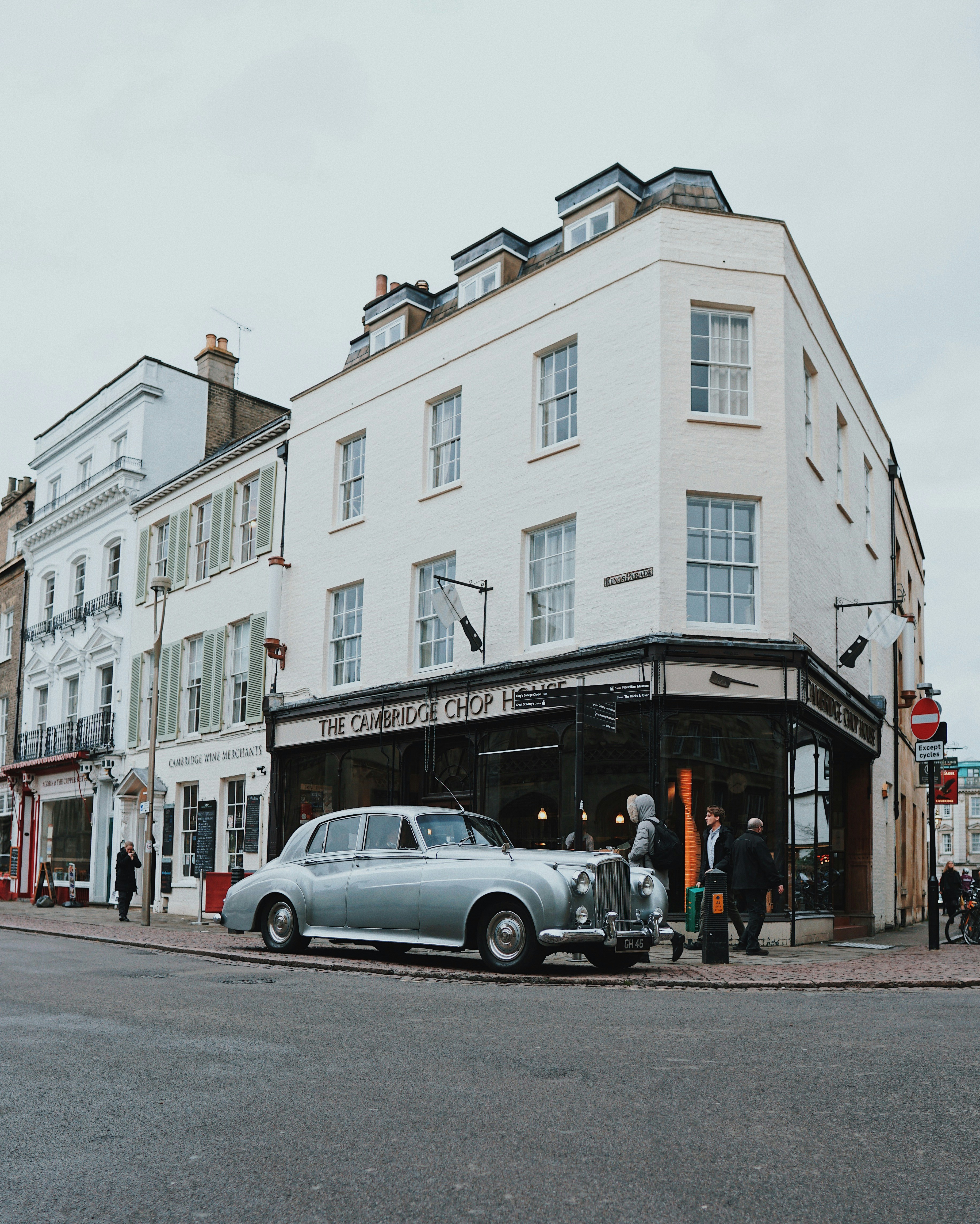Vintage car parked in front of a charming restaurant on a bustling street, showcasing architectural details and urban life.