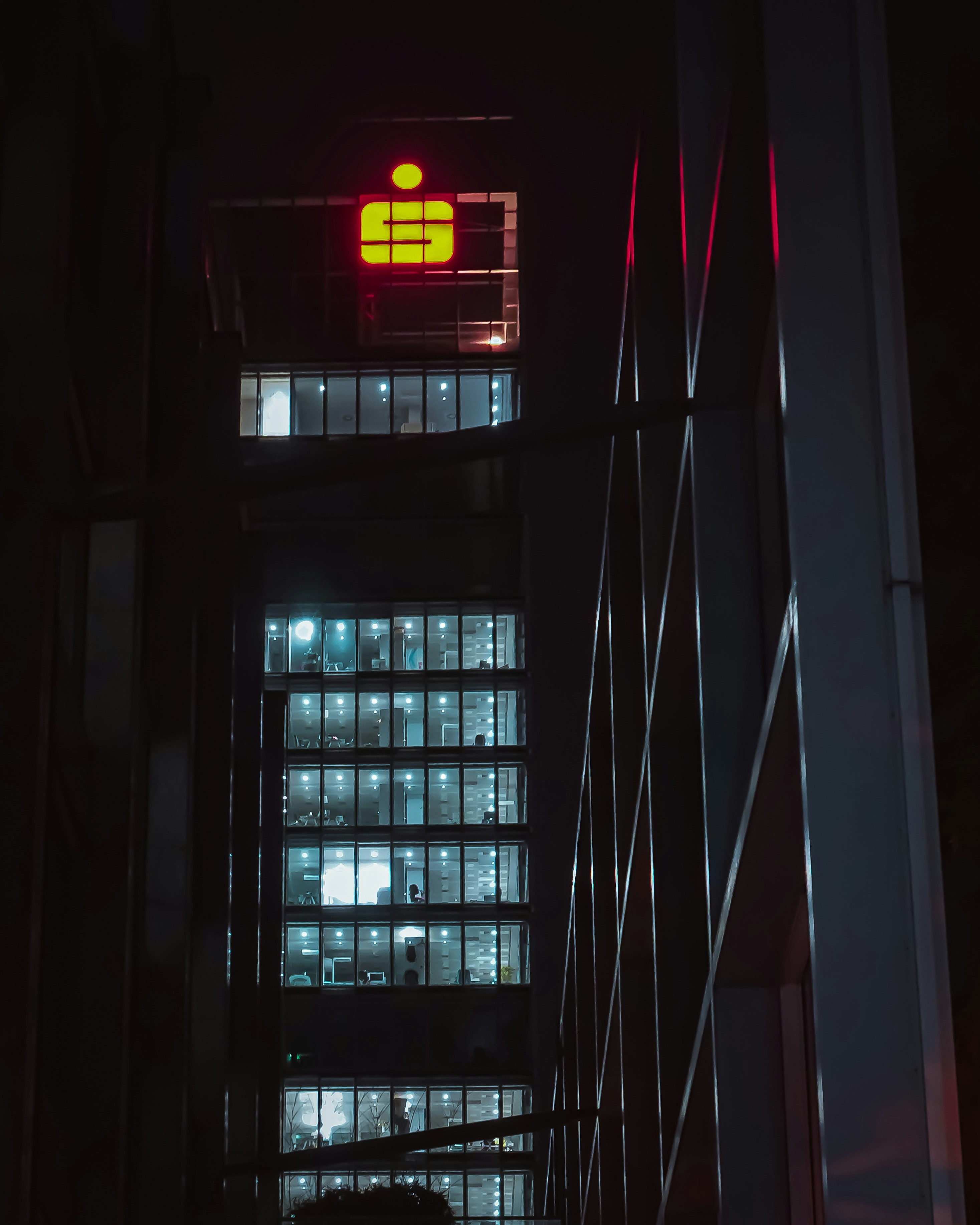 Midnight Grid: Blue Office Floors Framed by a Dark Atrium