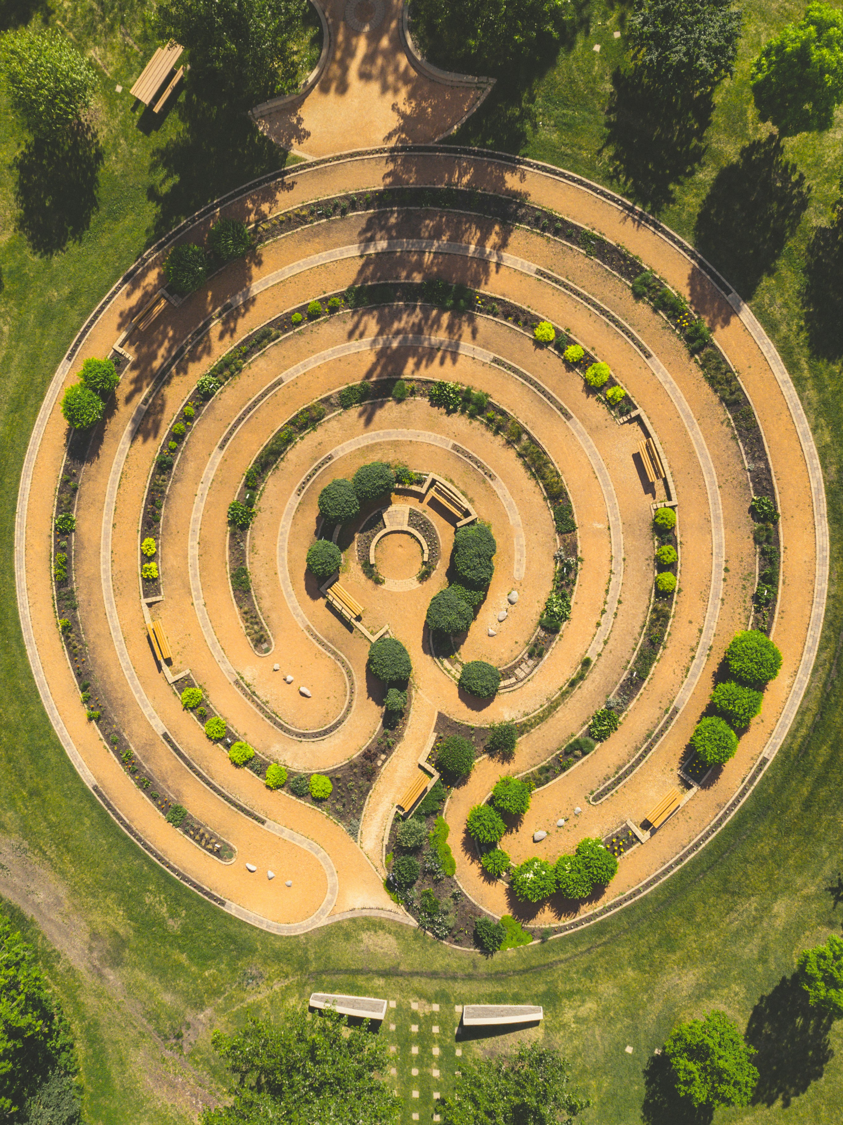 Aerial view of a beautifully designed labyrinth featuring winding paths, greenery, and benches, inviting contemplation and exploration.