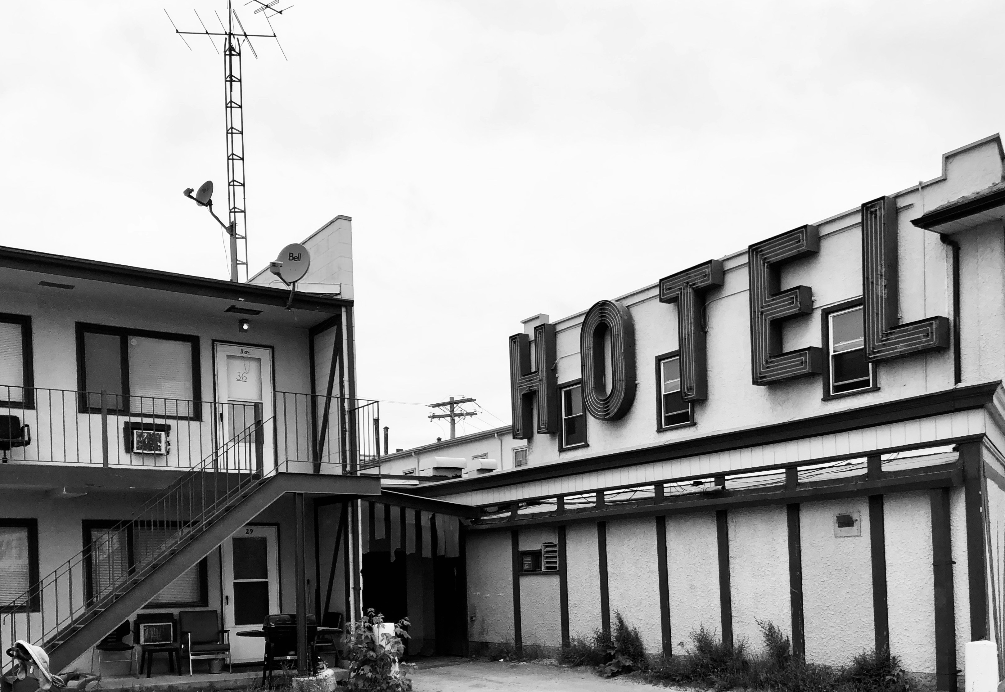 Grayscale photo of a mid-century motel with bold signage and outdoor staircases.