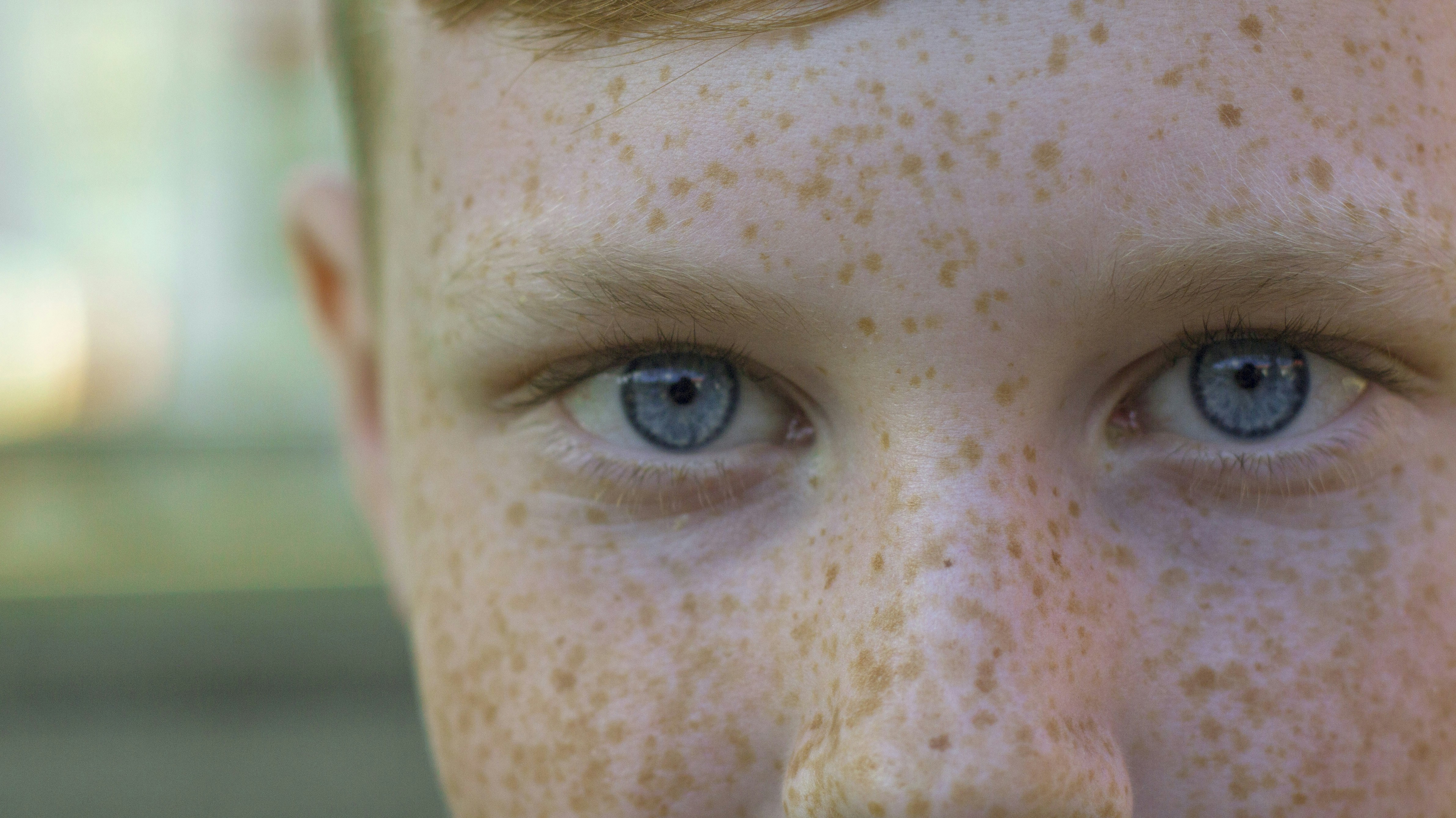 Close-up of a child's freckled face with bright blue eyes.