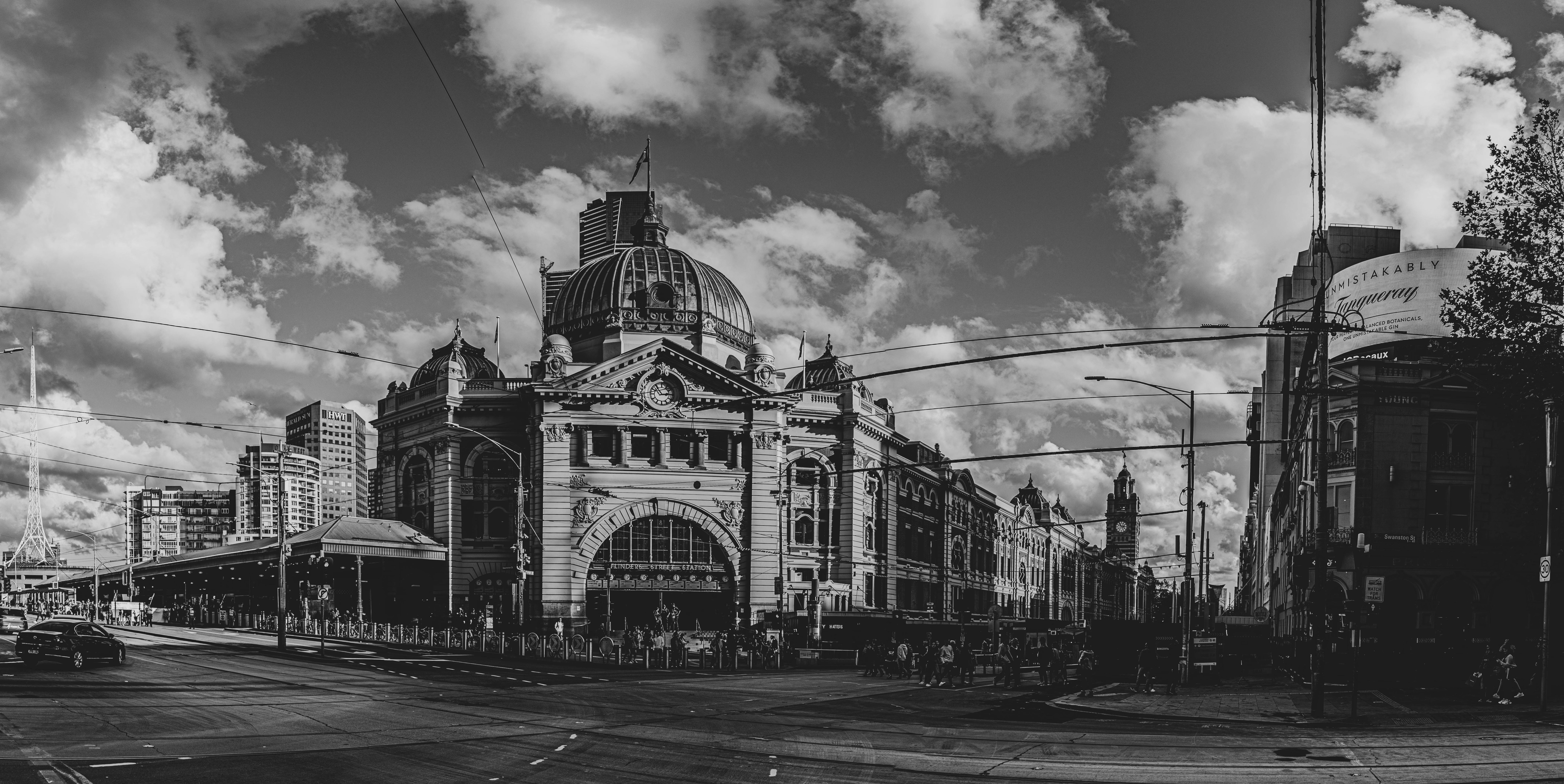 Grayscale cityscape featuring a grand, historic building beneath a dramatic cloudy sky.