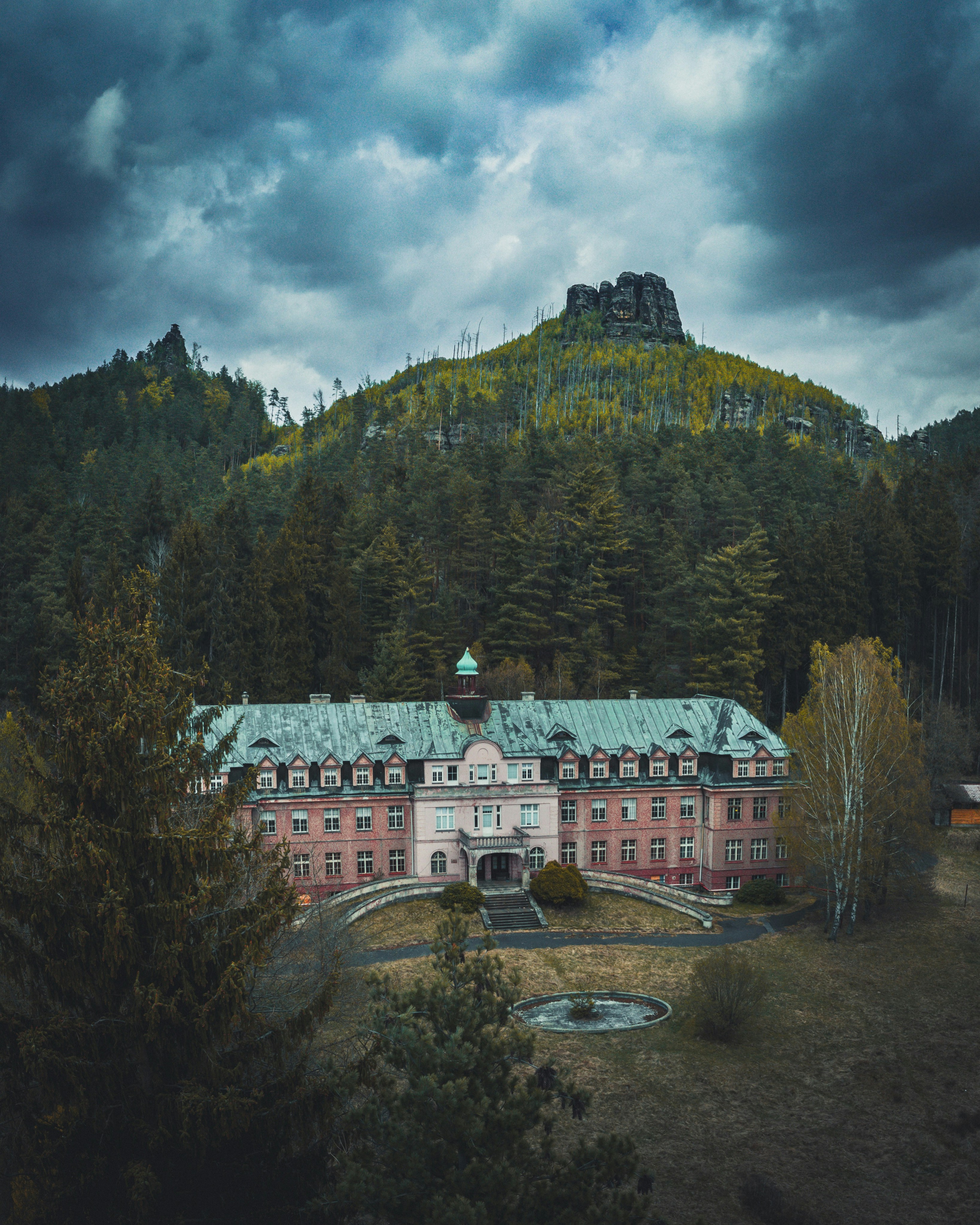 Pink Manor in the Pines: Forest-Fronted Estate Beneath a Cliff-Crowned Hill