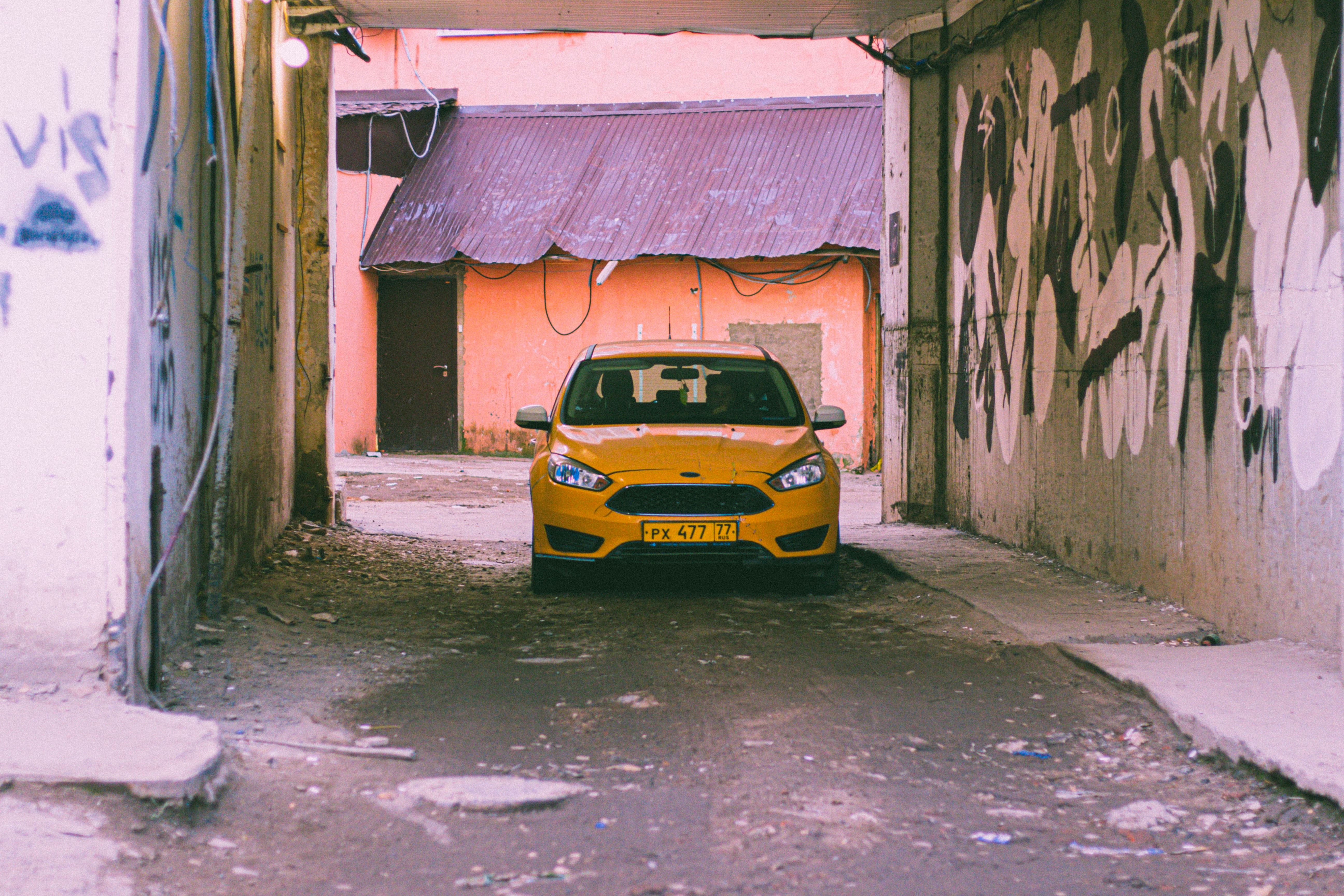 yellow car parked beside white wall