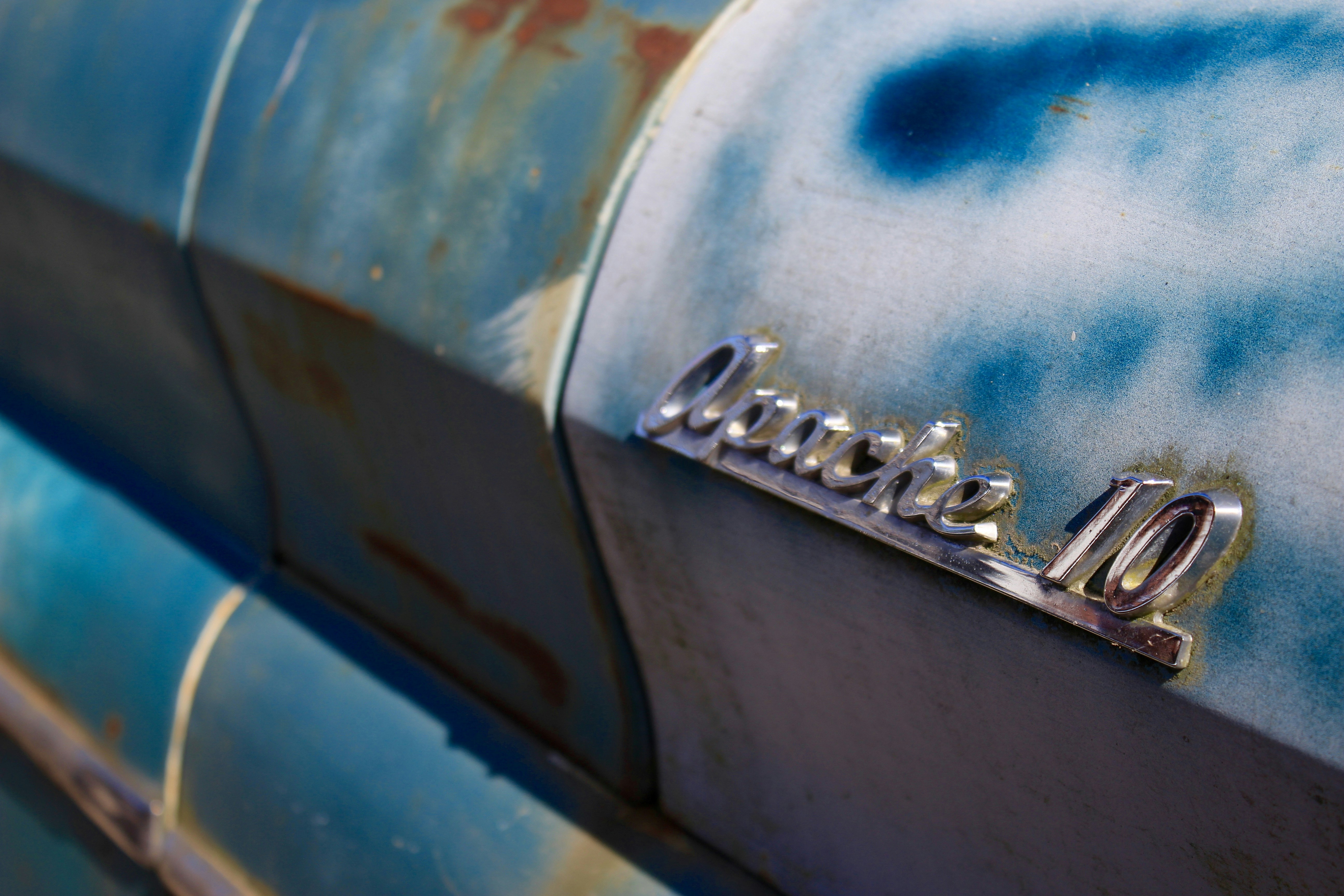 Close-up of a vintage pickup truck's badge, showcasing weathered paint and chrome detailing. The image captures the essence of nostalgia and automotive history.