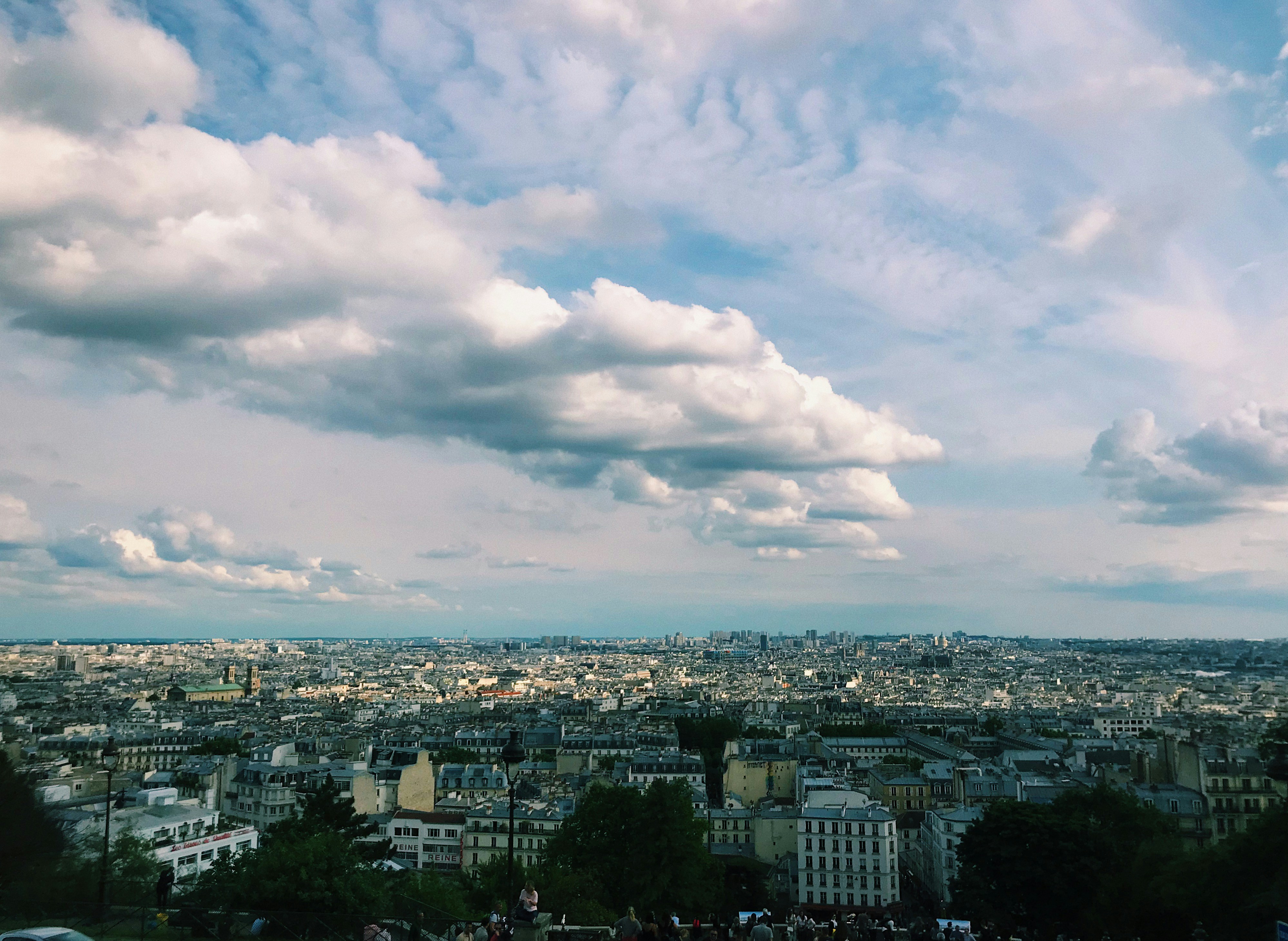 Expansive cityscape under a sky filled with dramatic clouds.