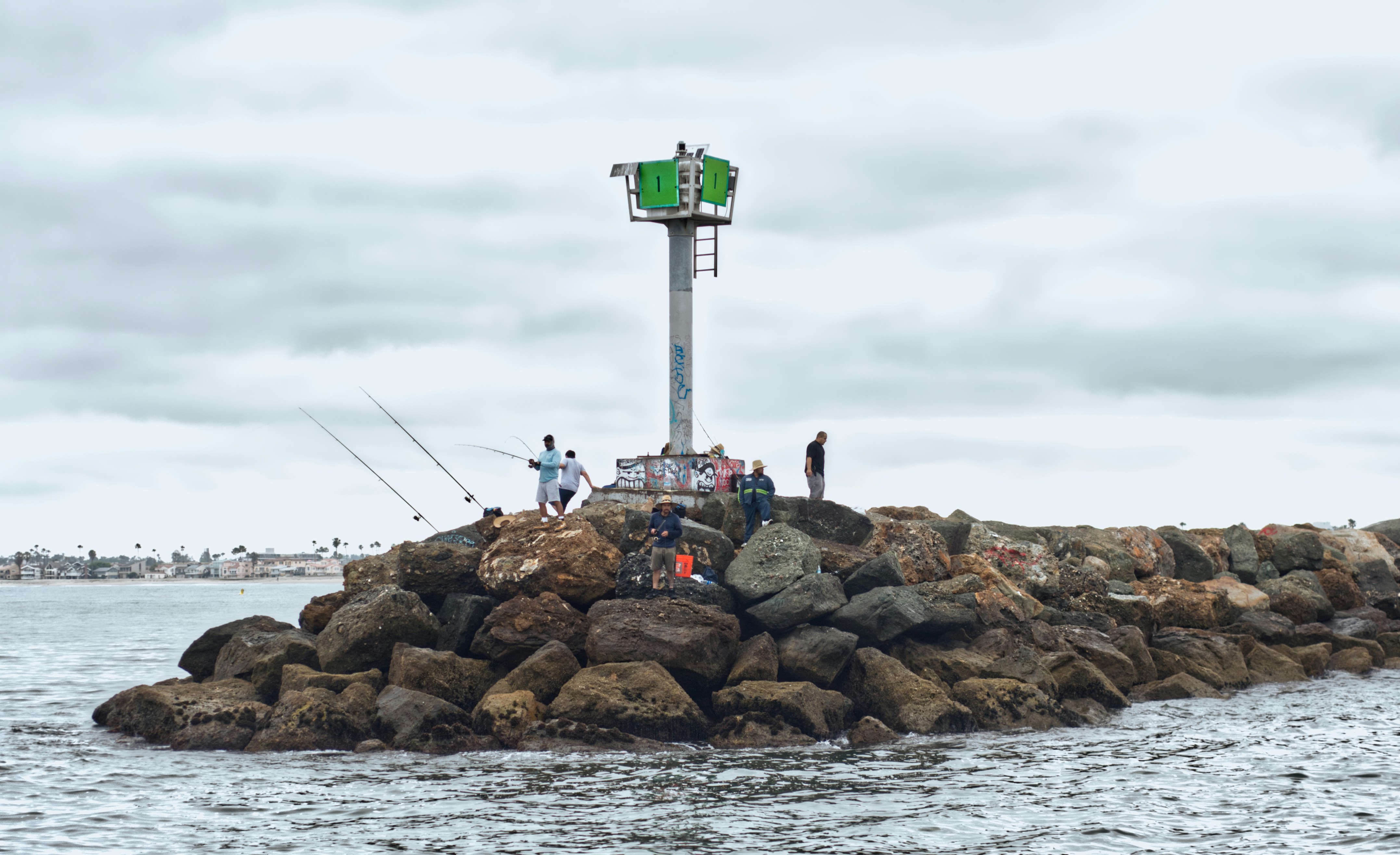 Green Beacon Over the Breakwater: Anglers on a Rugged Jetty
