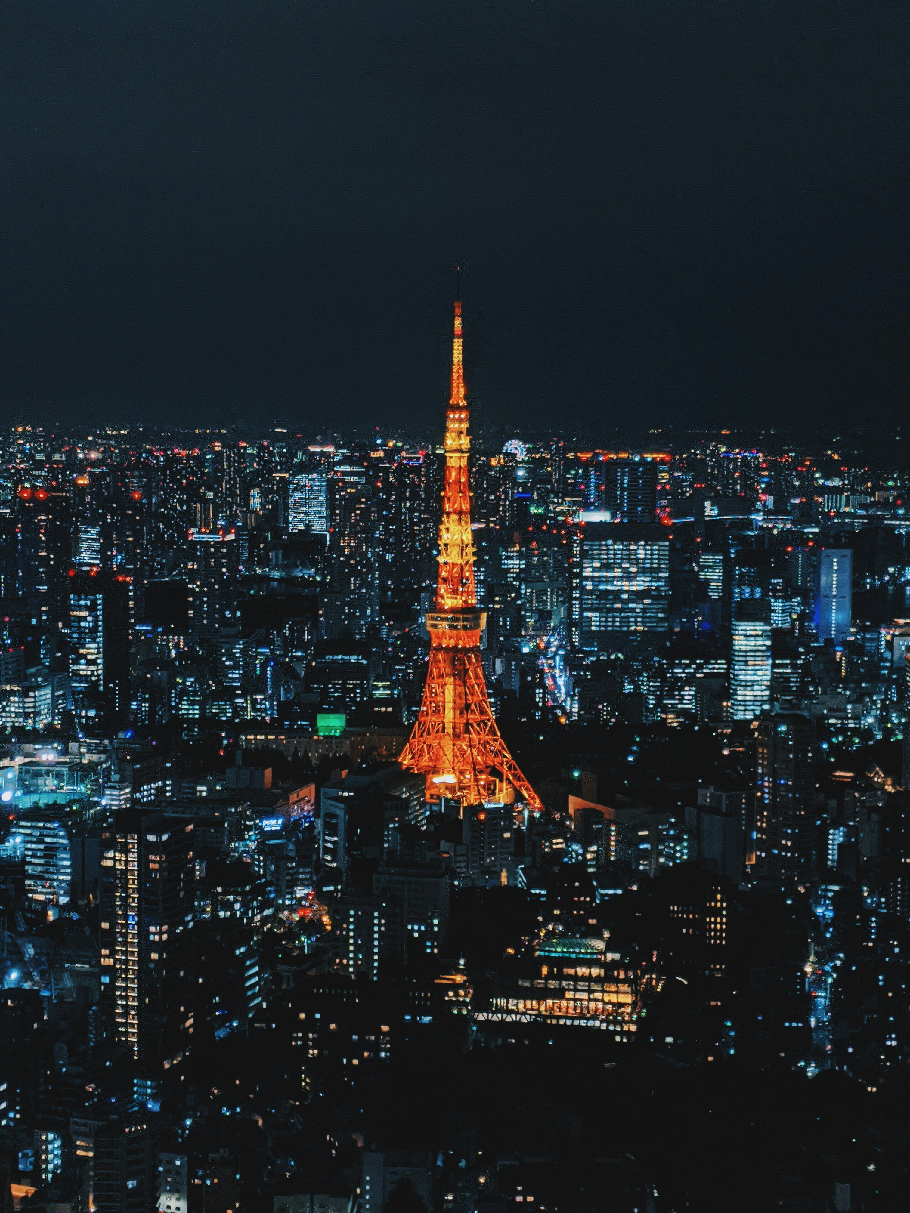 Tokyo Tower glowing amidst a sea of city lights at night, showcasing the vibrant urban landscape. The scene captures the essence of Tokyo’s nightlife.