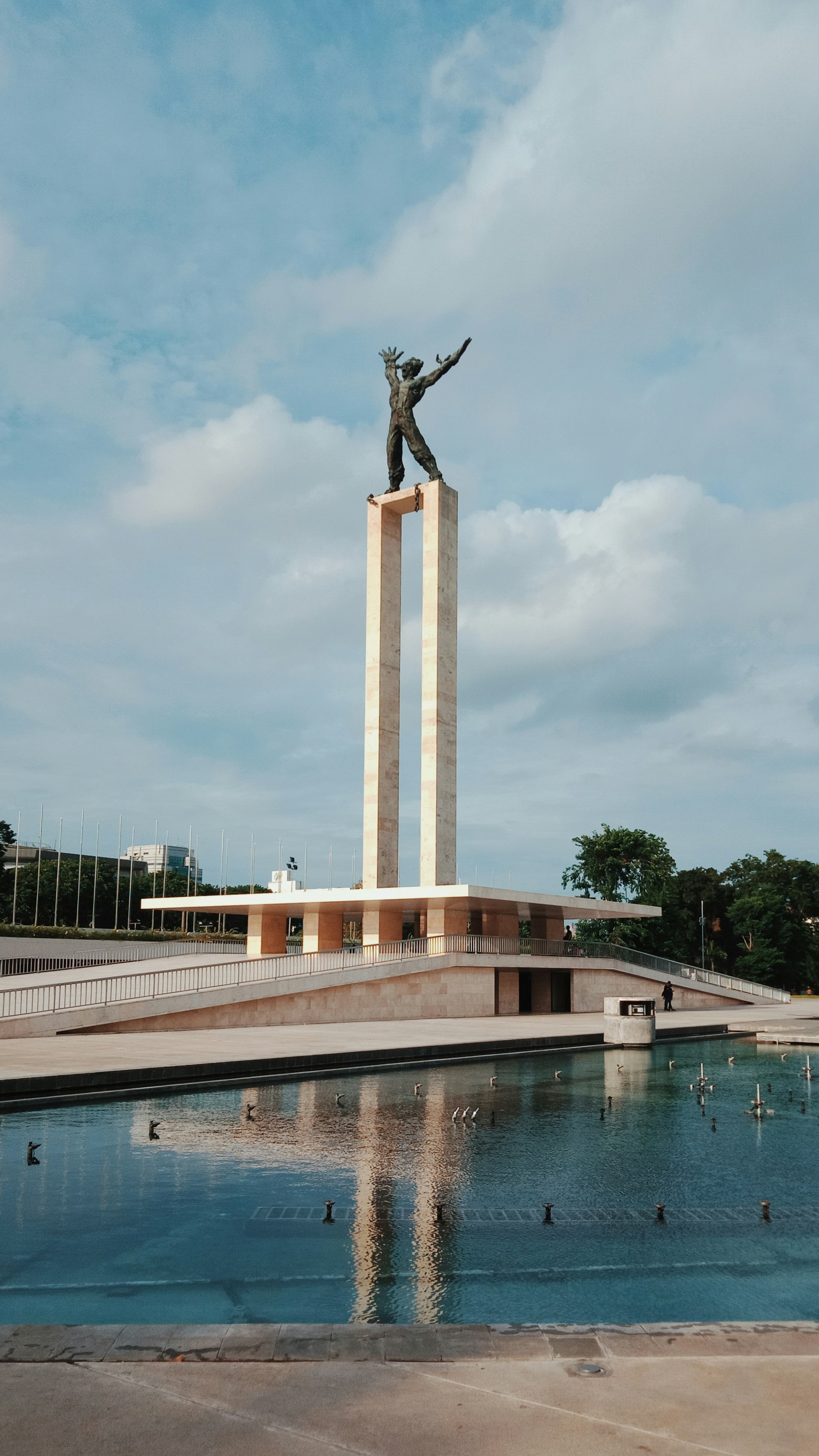 Monumen Pembebasan Irian Jaya di tengah Taman Lapangan Banteng. dibangun pada tahun 1963. | brown concrete monument near body of water during daytime